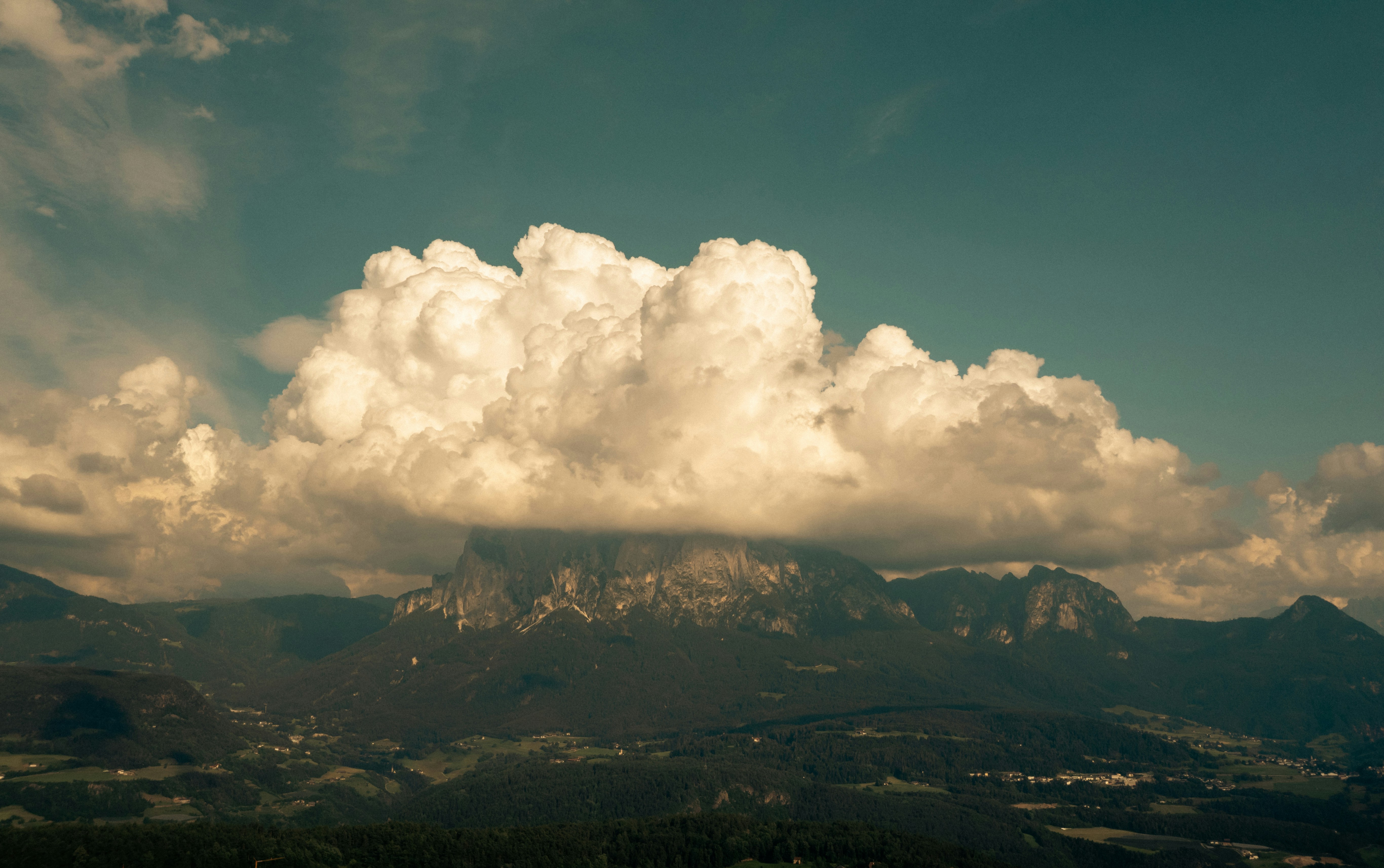 Hat! | Fluffy clouds cover majestic mountain range under blue sky