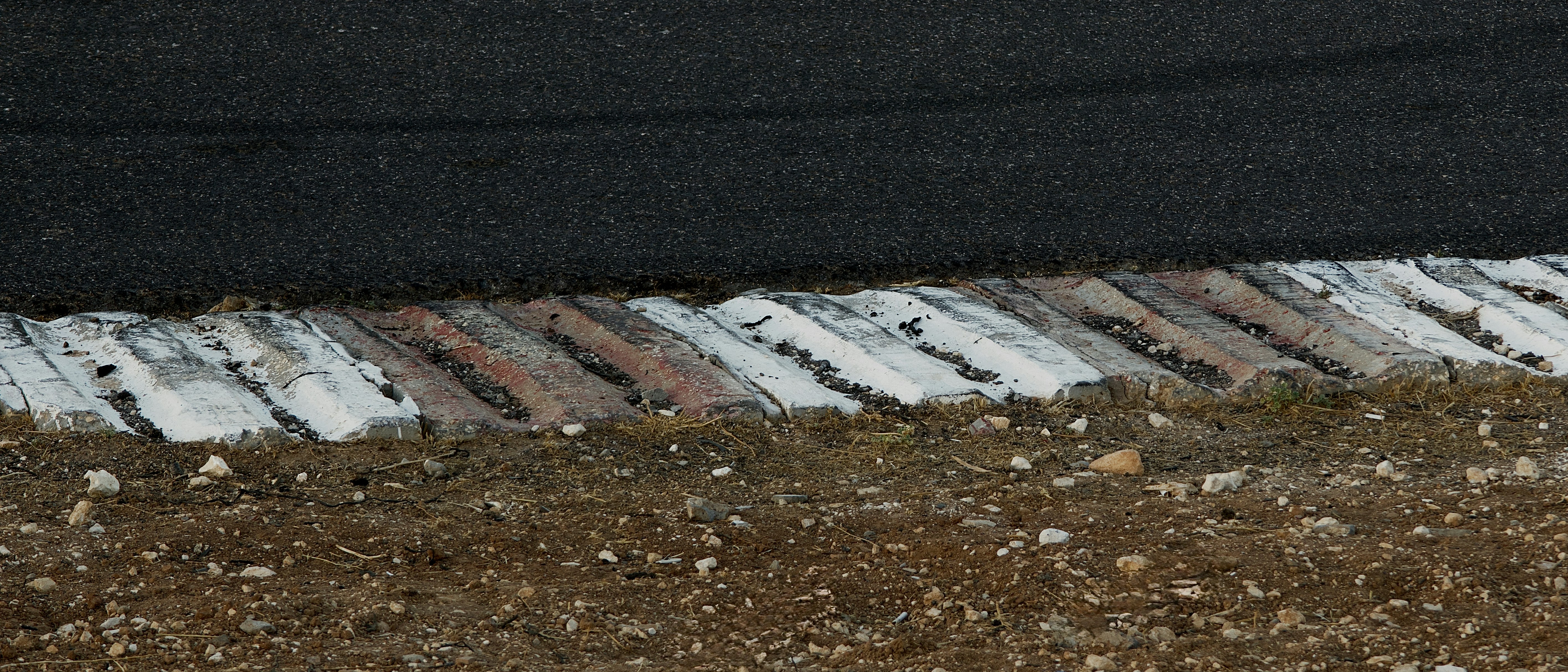 A race track curb with asphalt and gravel.