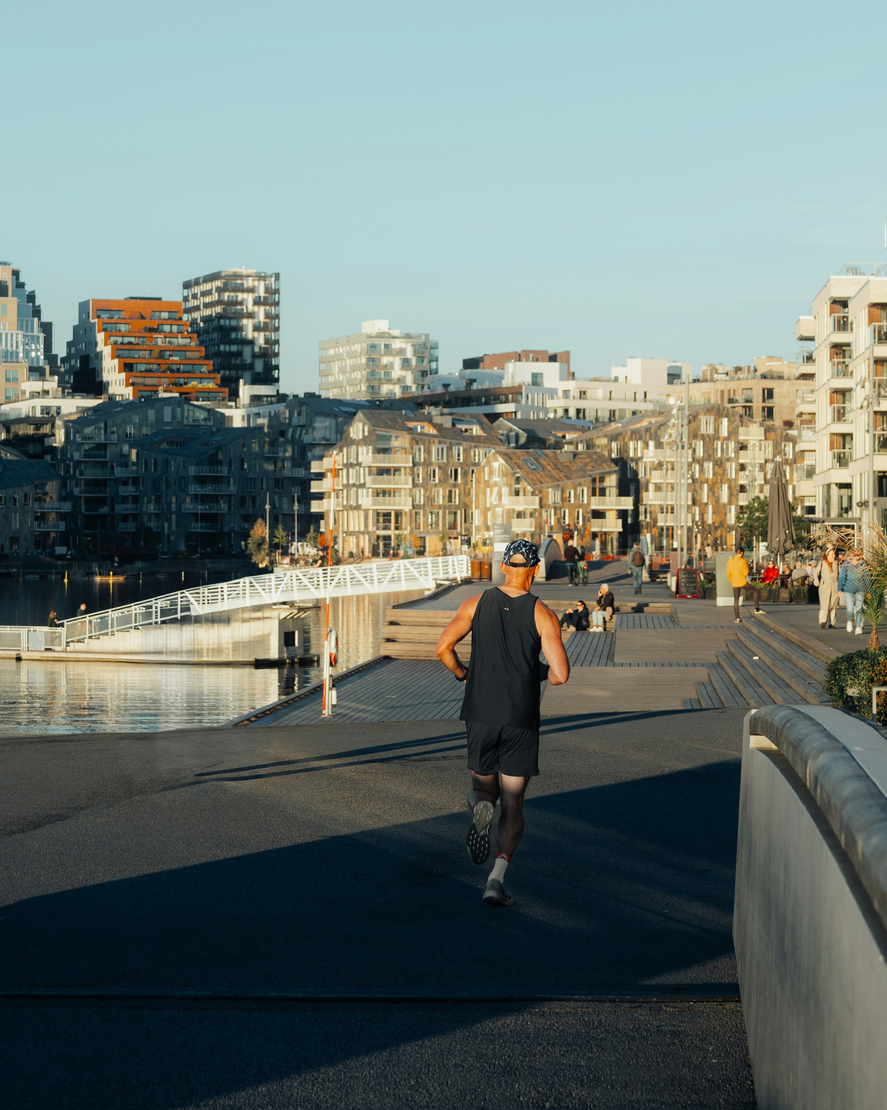 Man running along waterfront with city buildings.