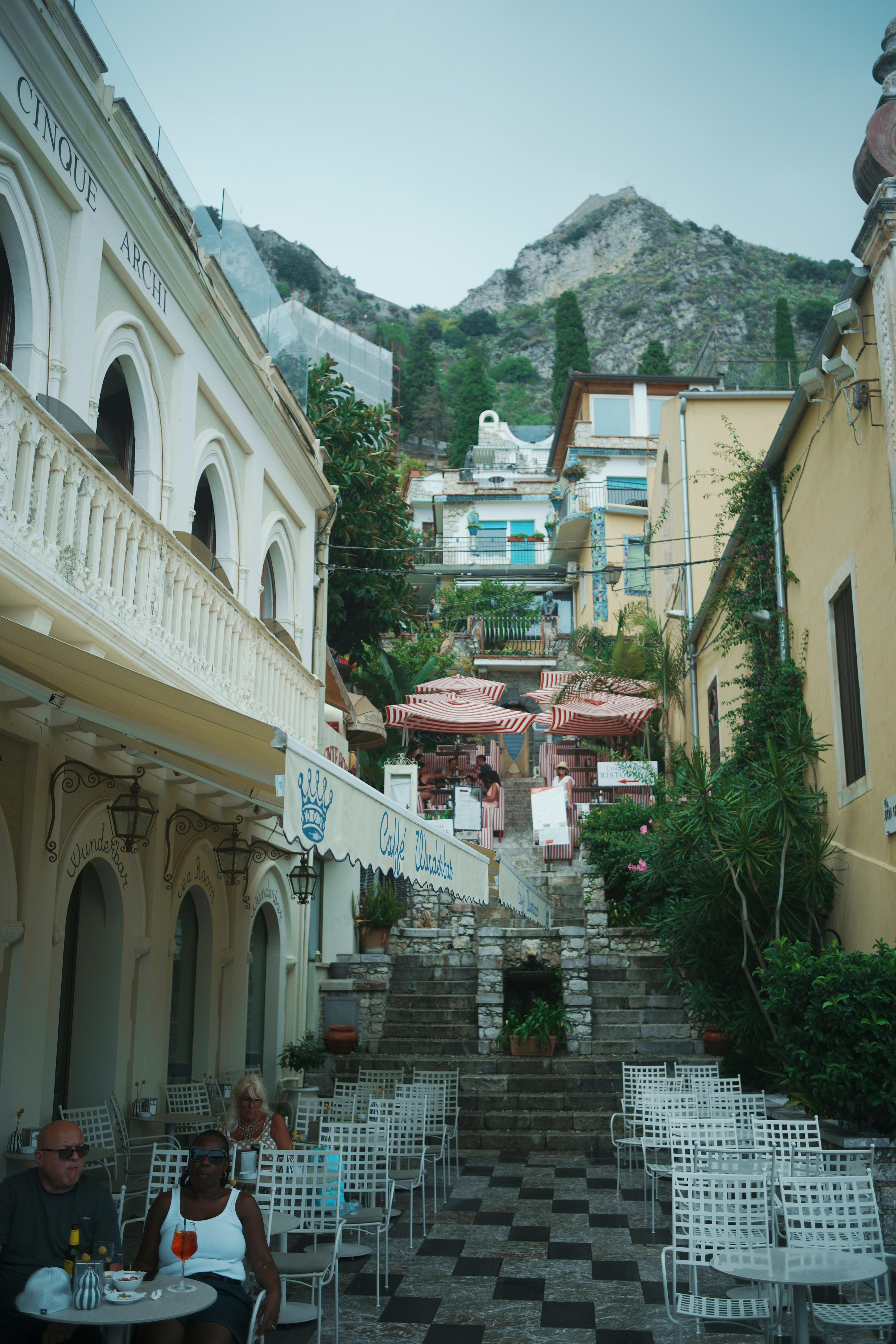 Outdoor cafe with people and stairs leading uphill.