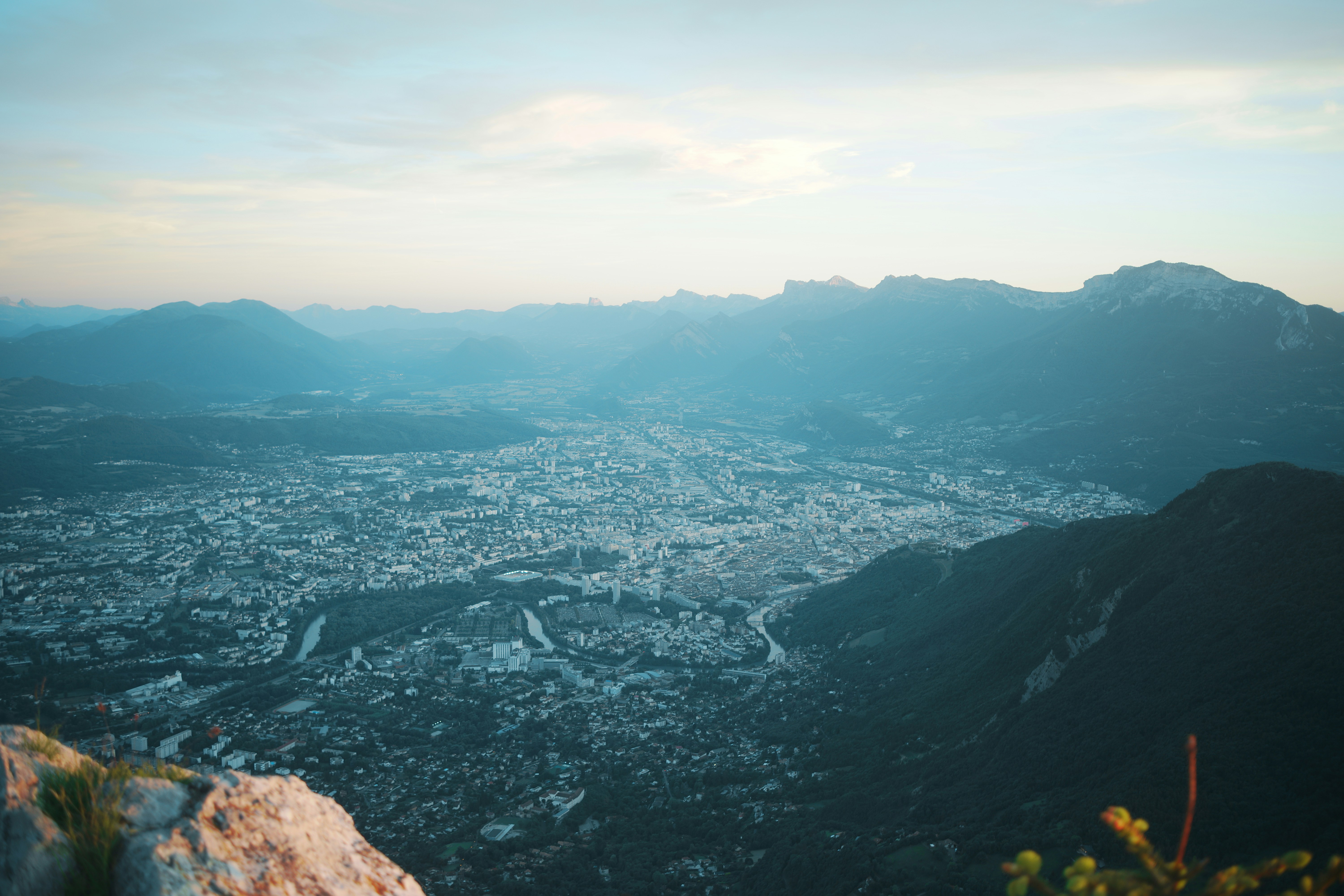City nestled in a valley with mountains at sunset.