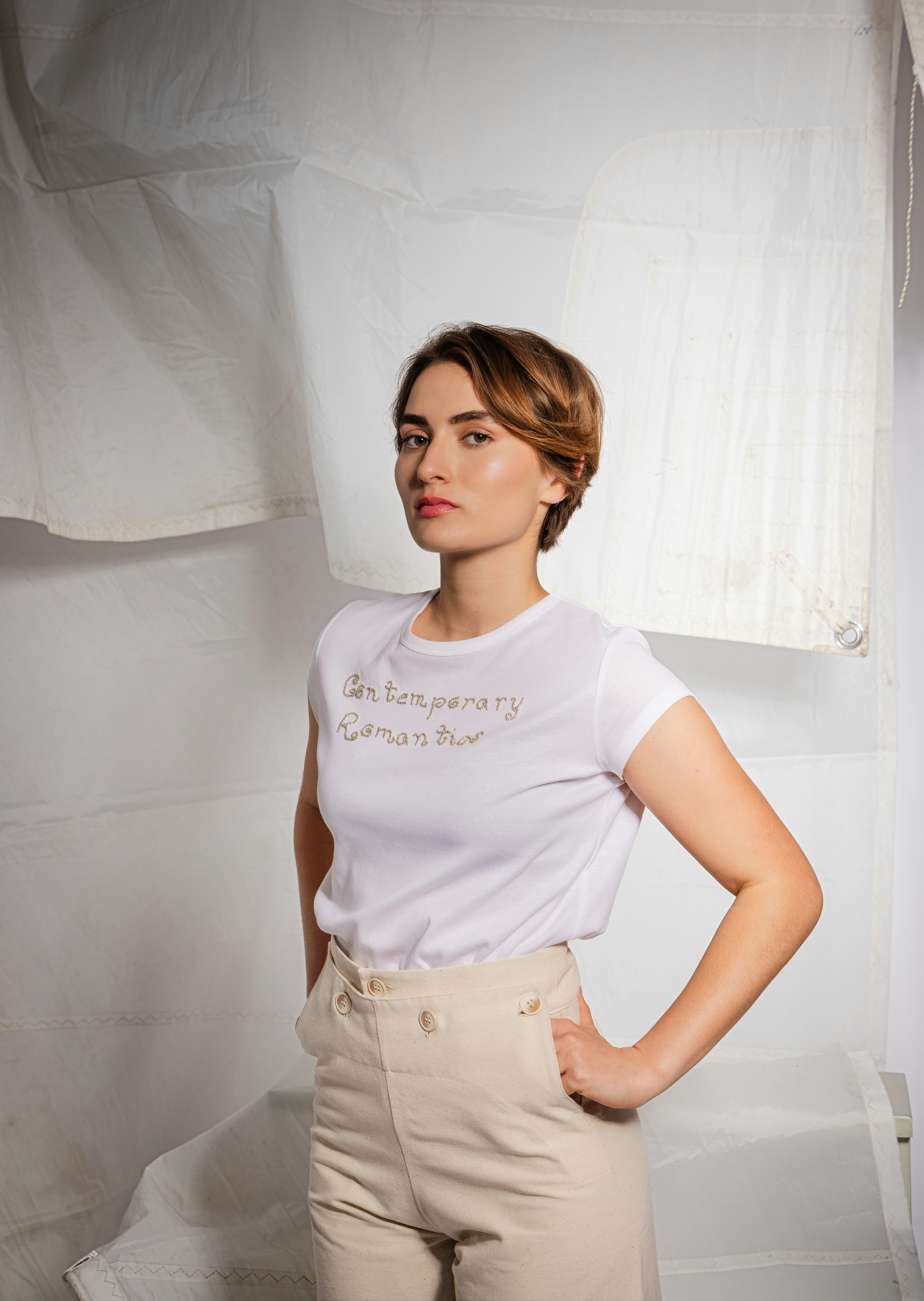 Woman in white t-shirt and beige pants poses confidently.