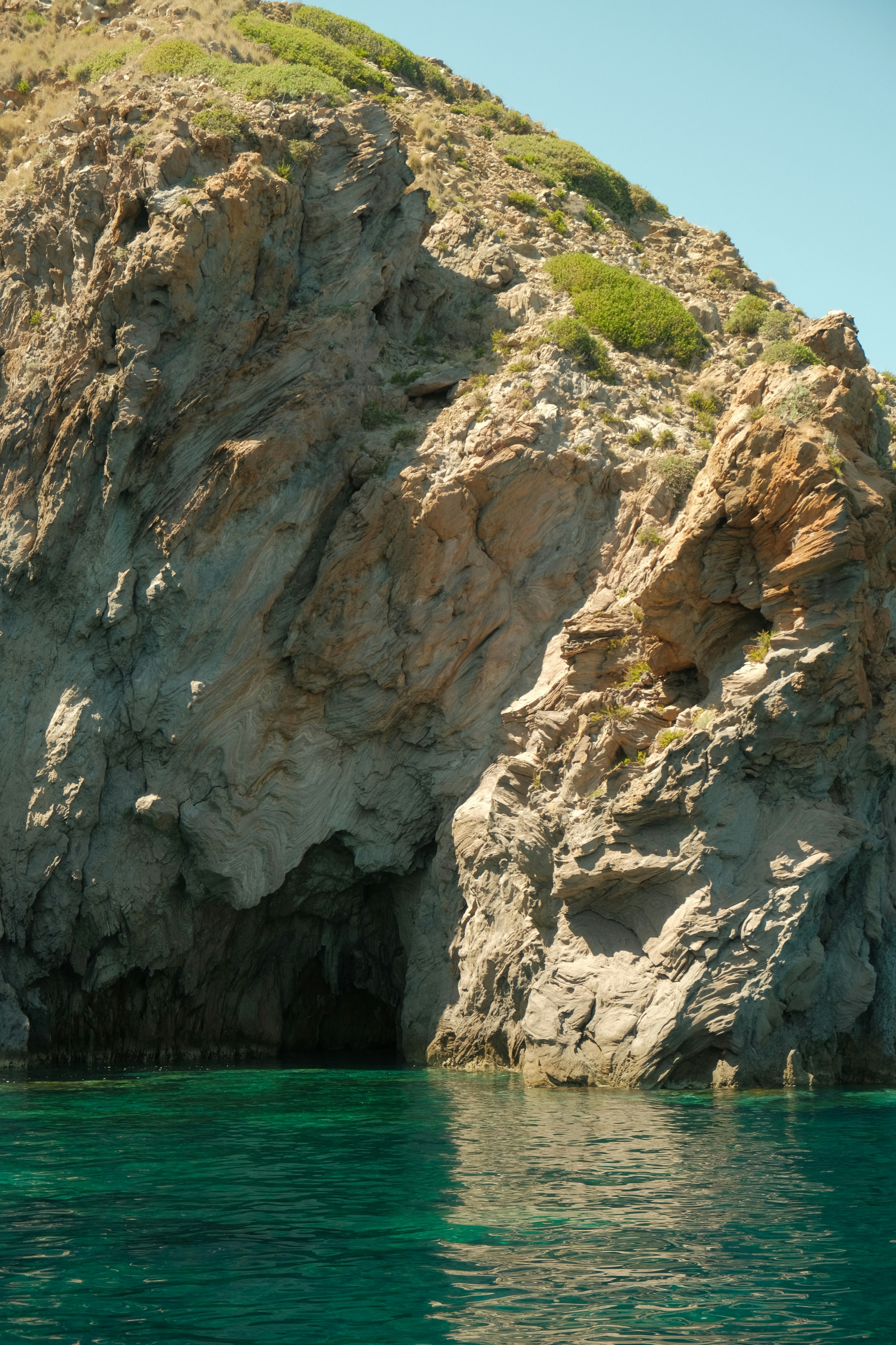 Rocky cliff face with a cave entrance by the sea