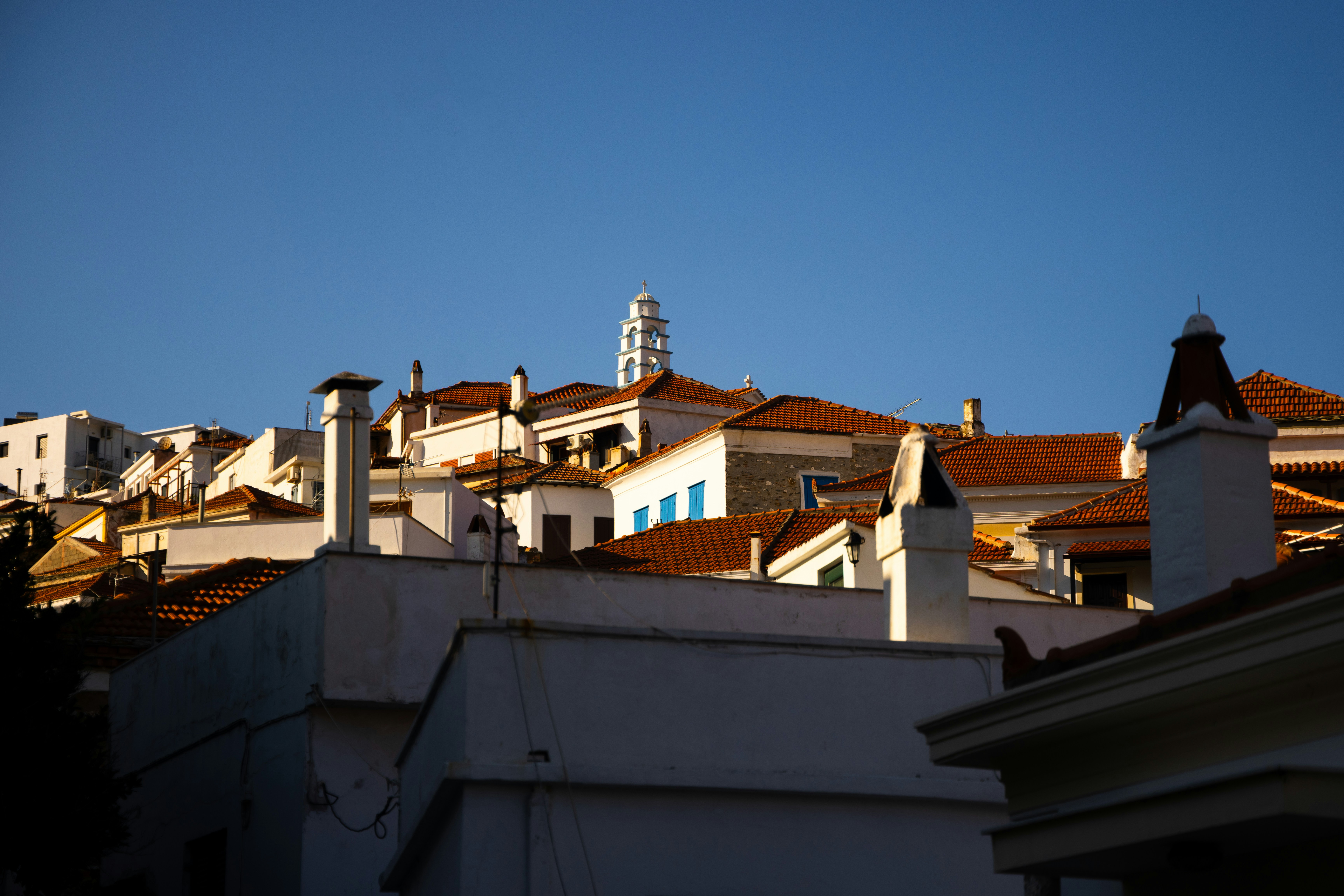 Rooftops of a mediterranean town under clear blue sky.