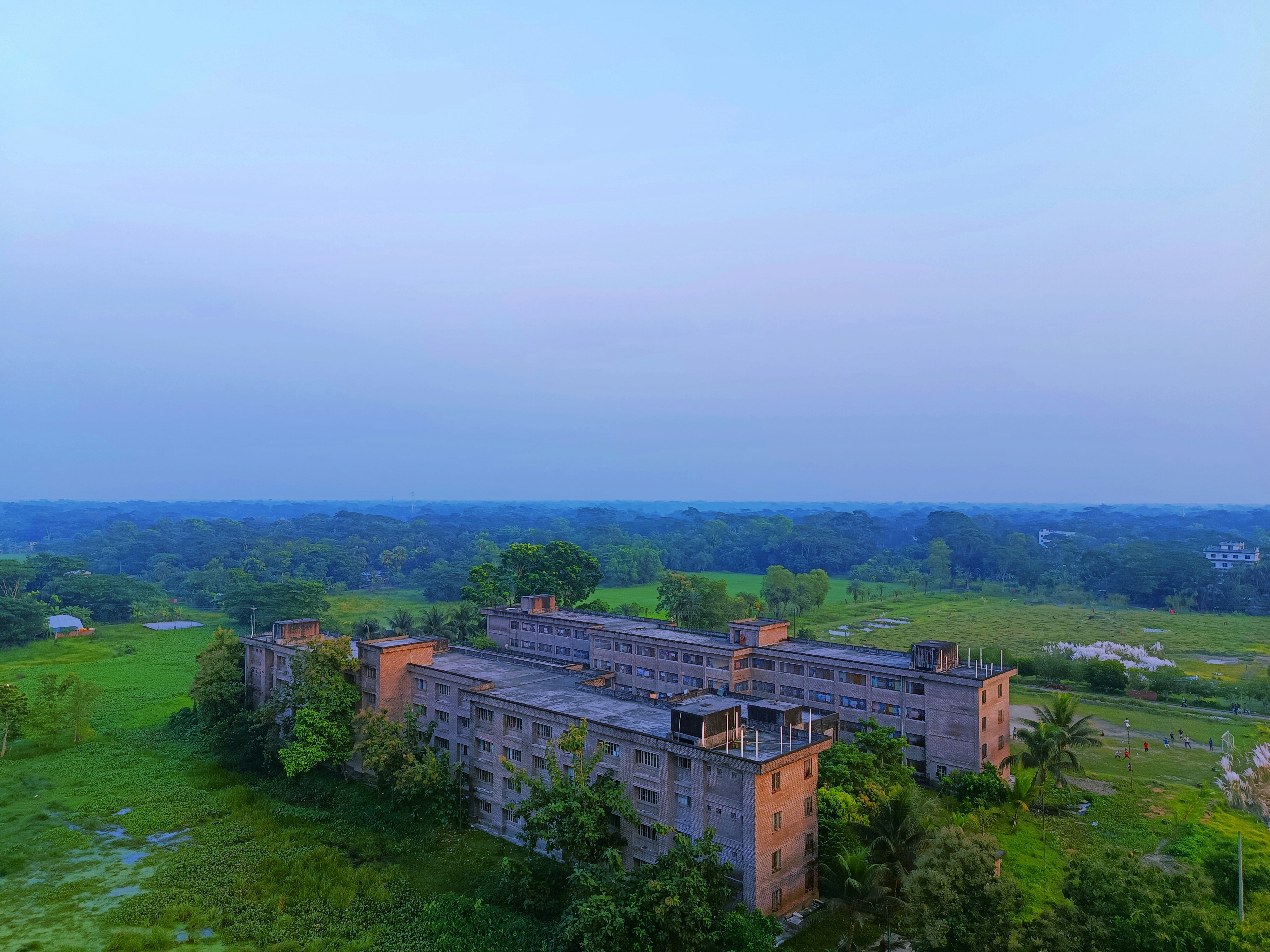 Bricked Campus Wings Amid Verdant Fields Under a Quiet Gradient Sky