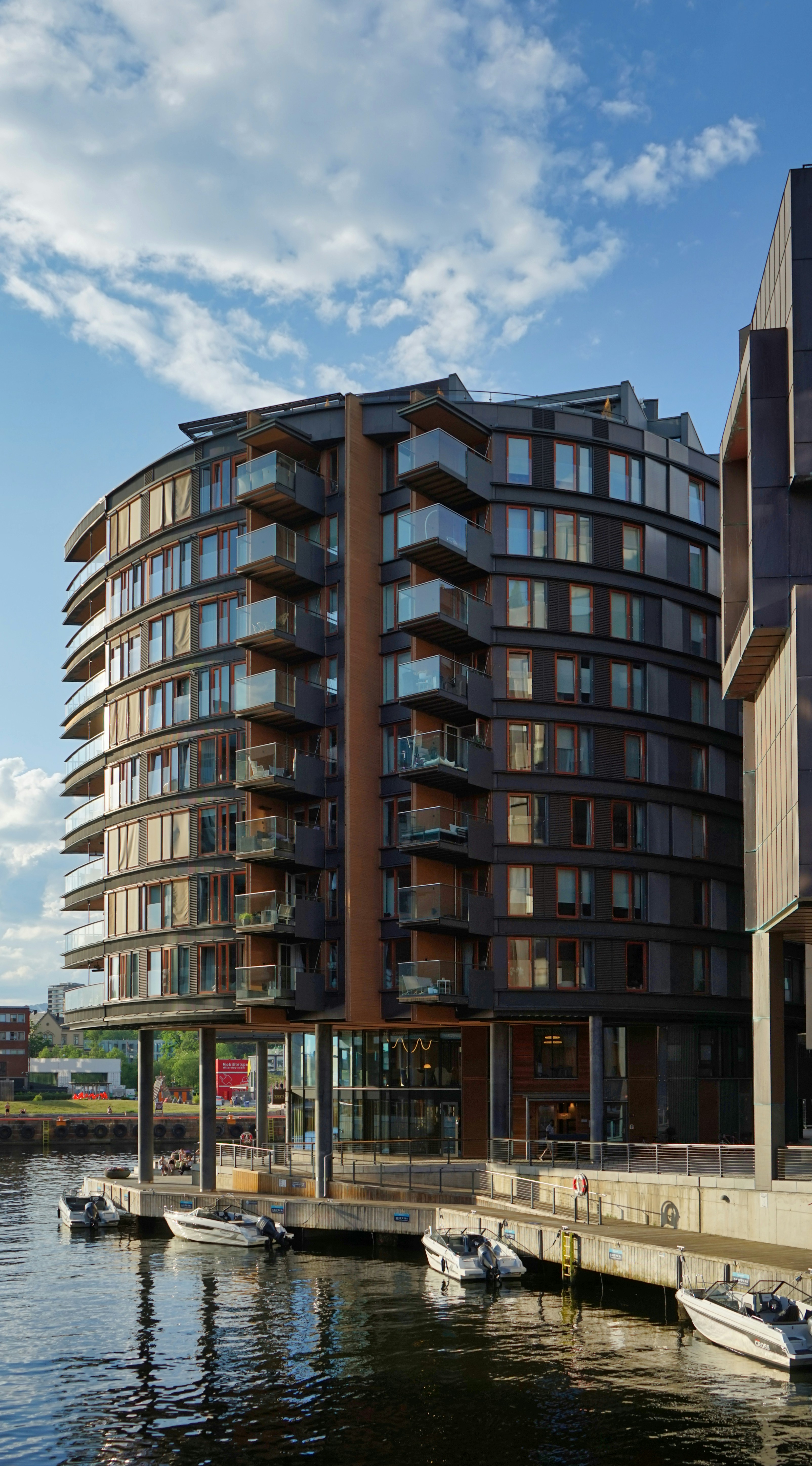 Modern curved building with balconies by the water.