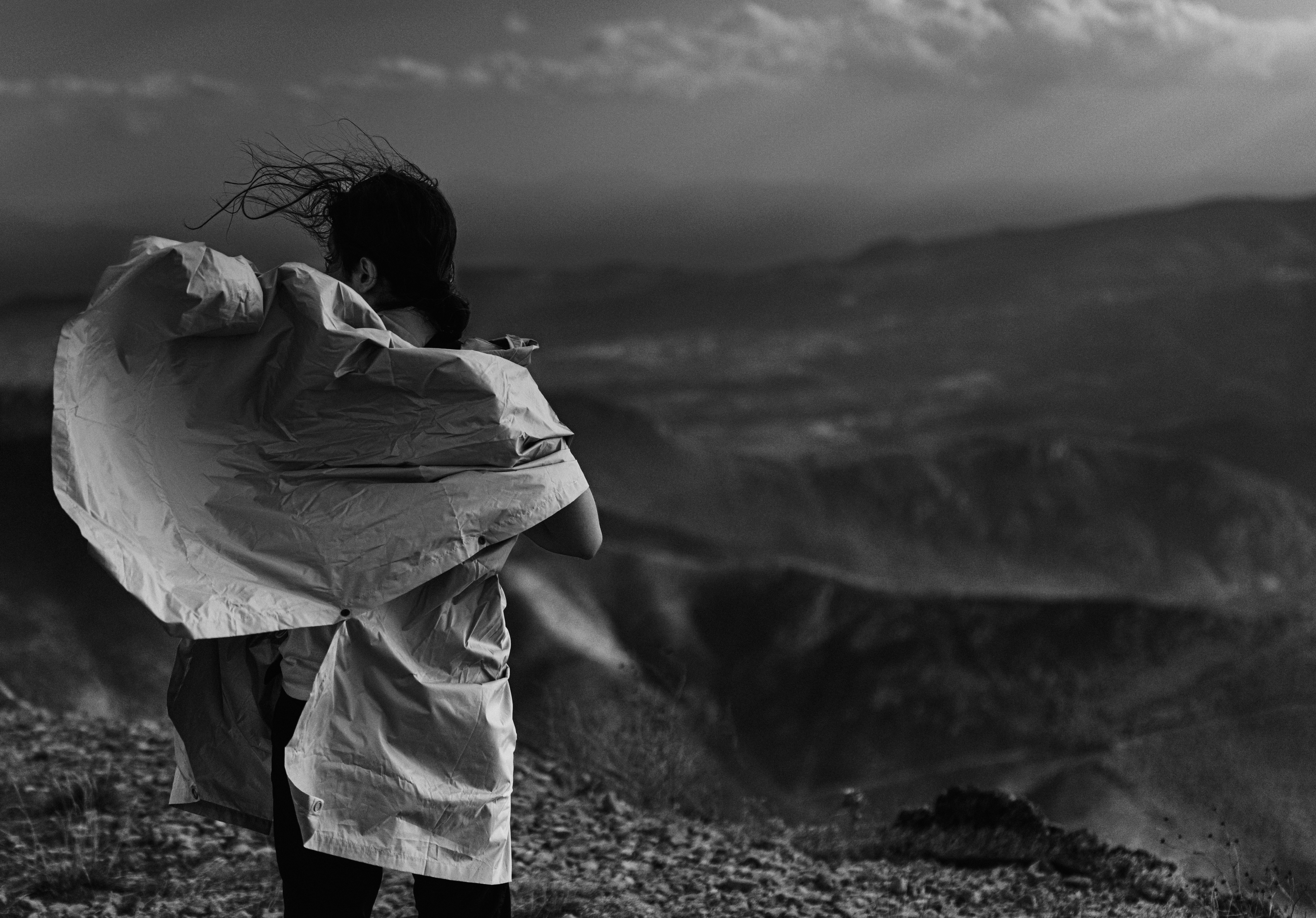 Woman in white cloth on windy mountain overlook