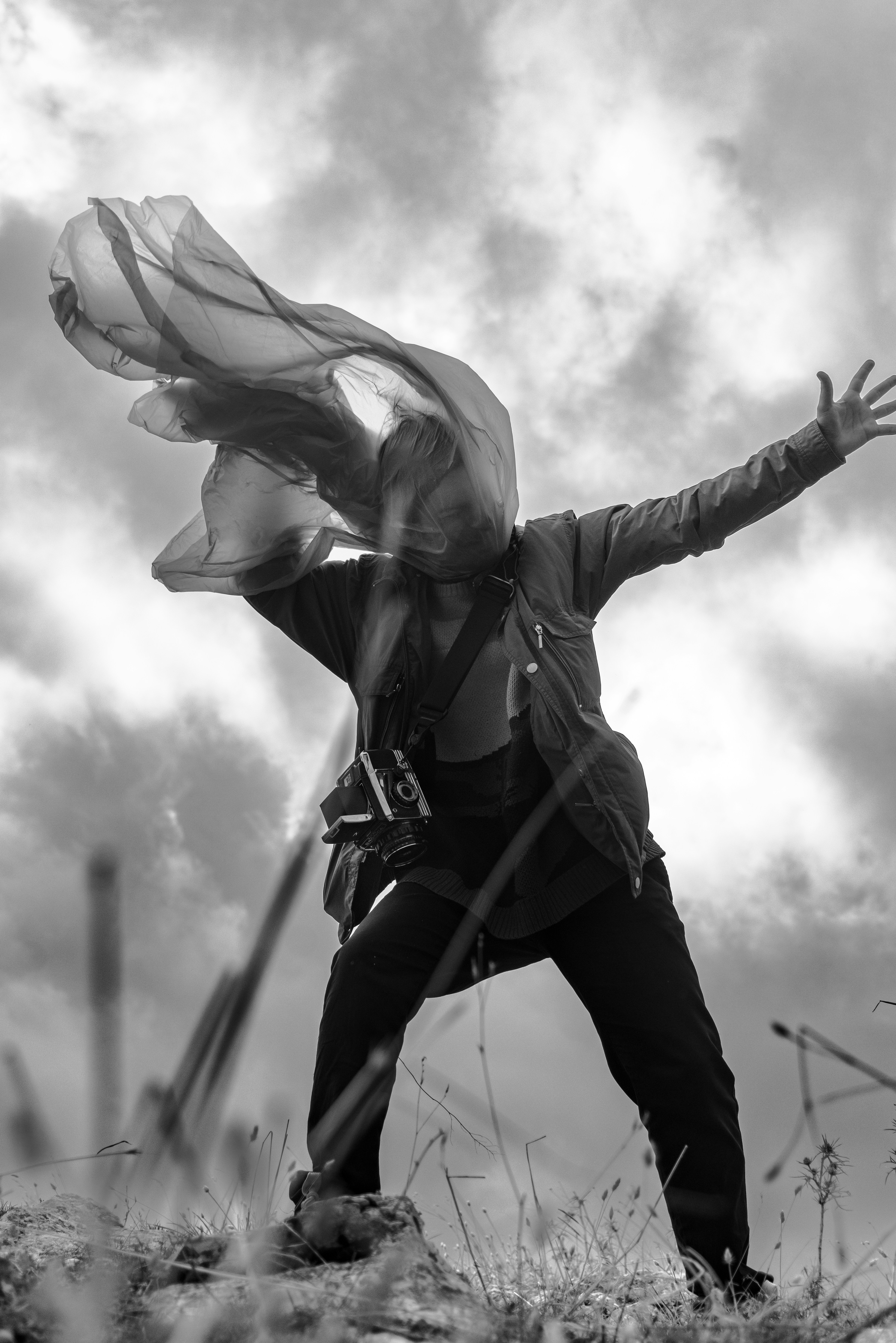 A figure in motion, draped in flowing fabric, expresses freedom against a dramatic cloudy backdrop. The scene captures a moment of artistic liberation.