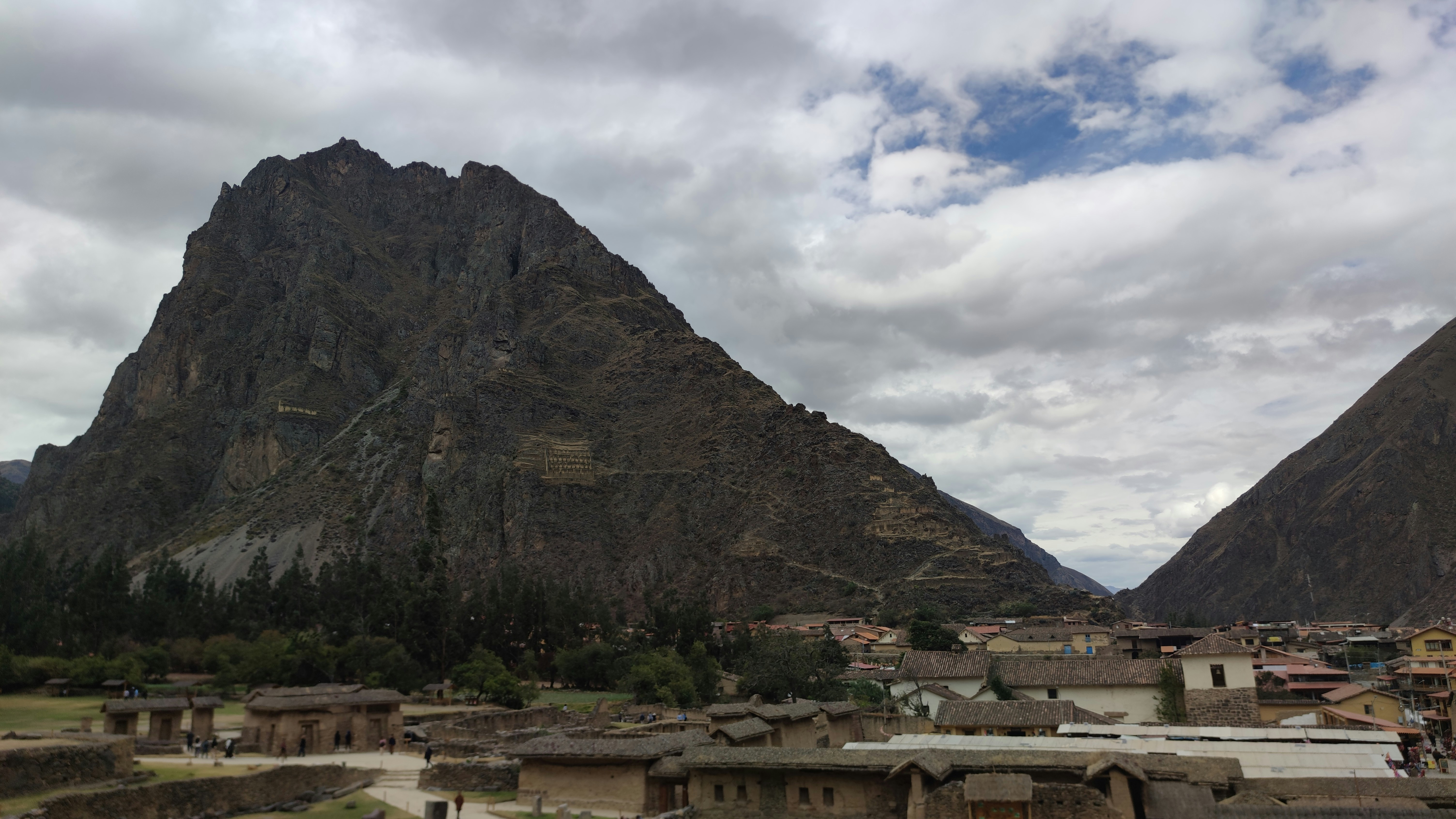 Ollantaytambo, Perù ~ 18 August 2025 | A large mountain overlooks a village under a cloudy sky