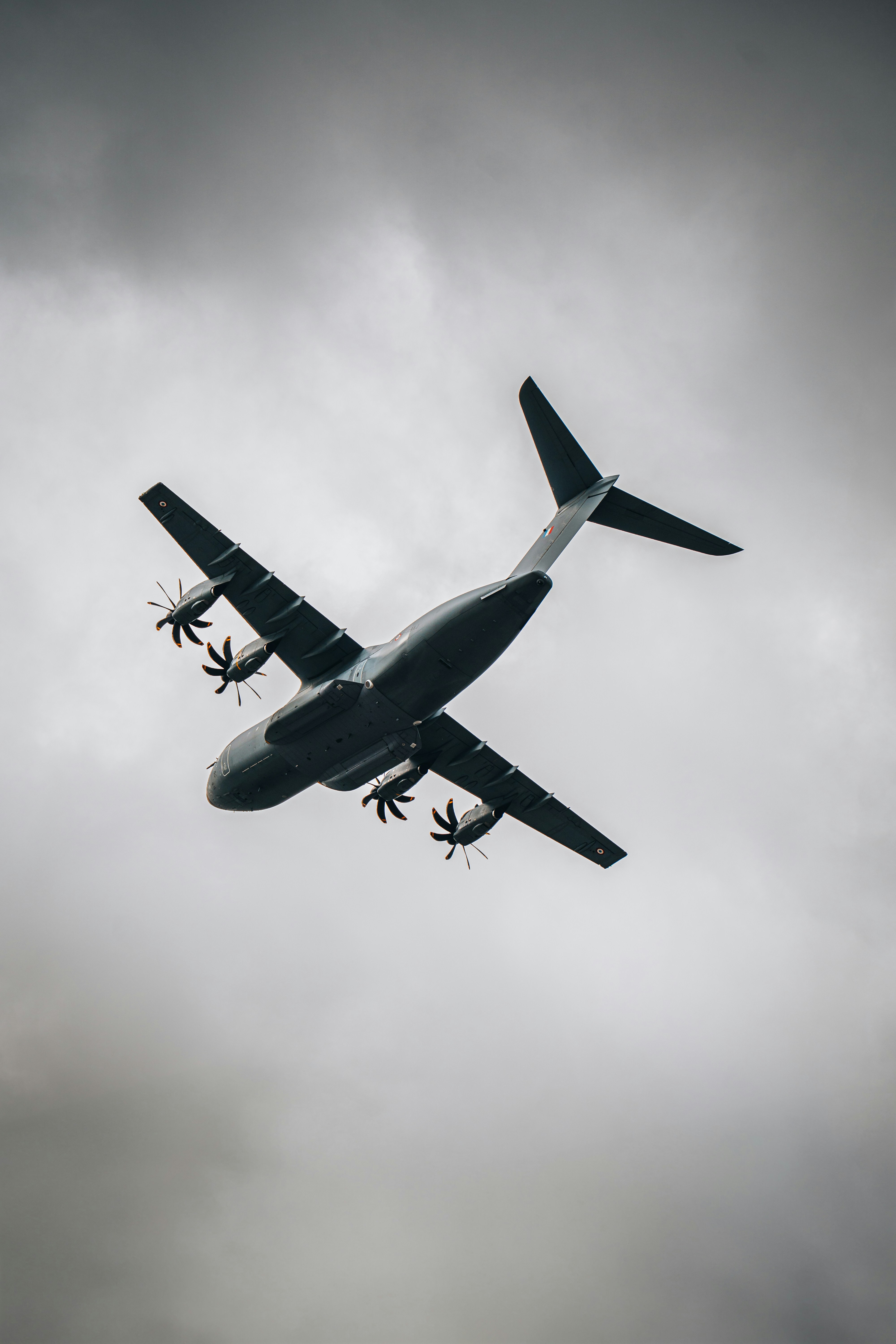 Military transport aircraft flying against a backdrop of overcast skies, showcasing its powerful design and engineering.