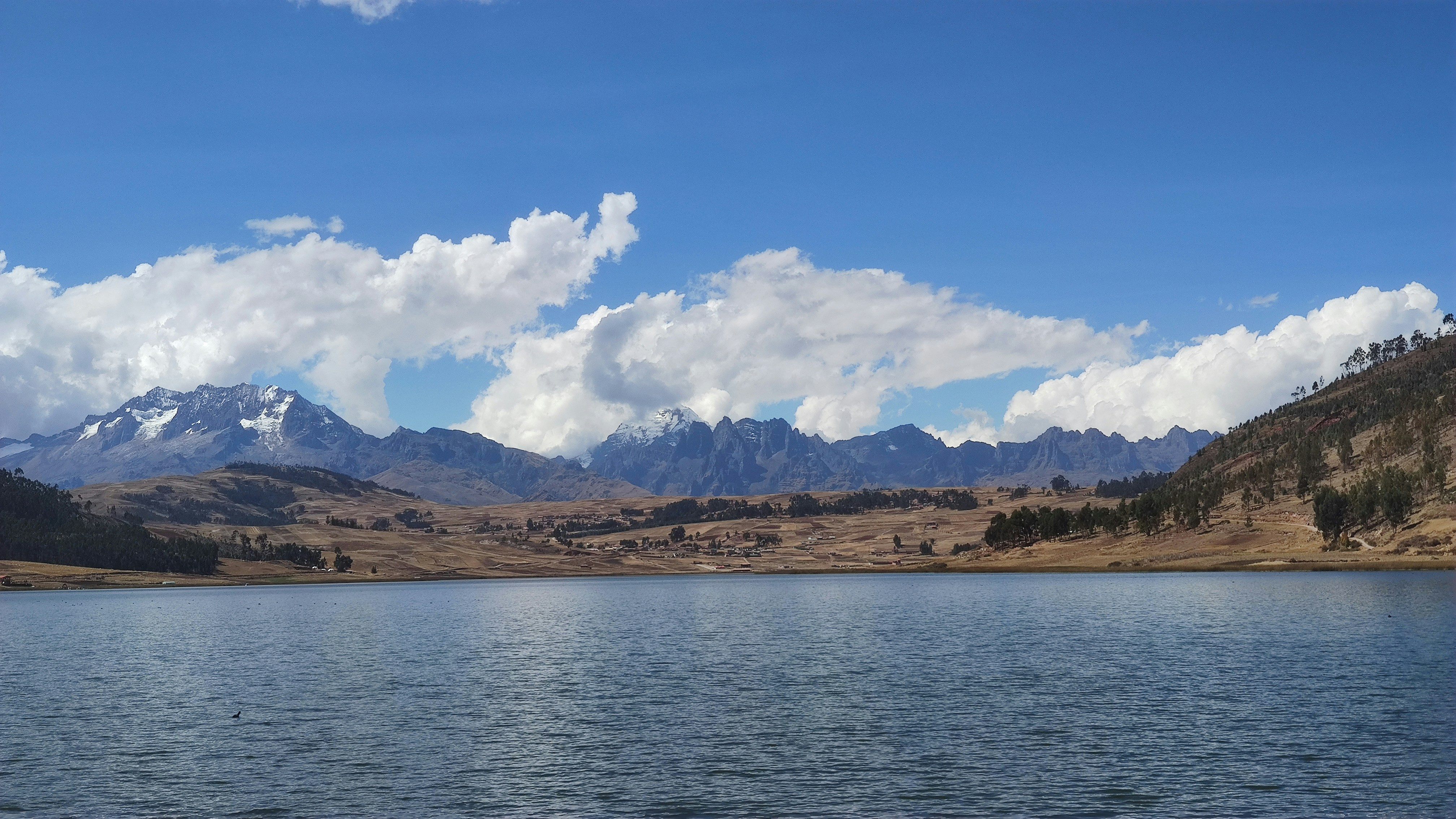 Laguna Huaypo, Perù ~ 19 August 2025 | A calm lake reflects the mountains under a cloudy sky.