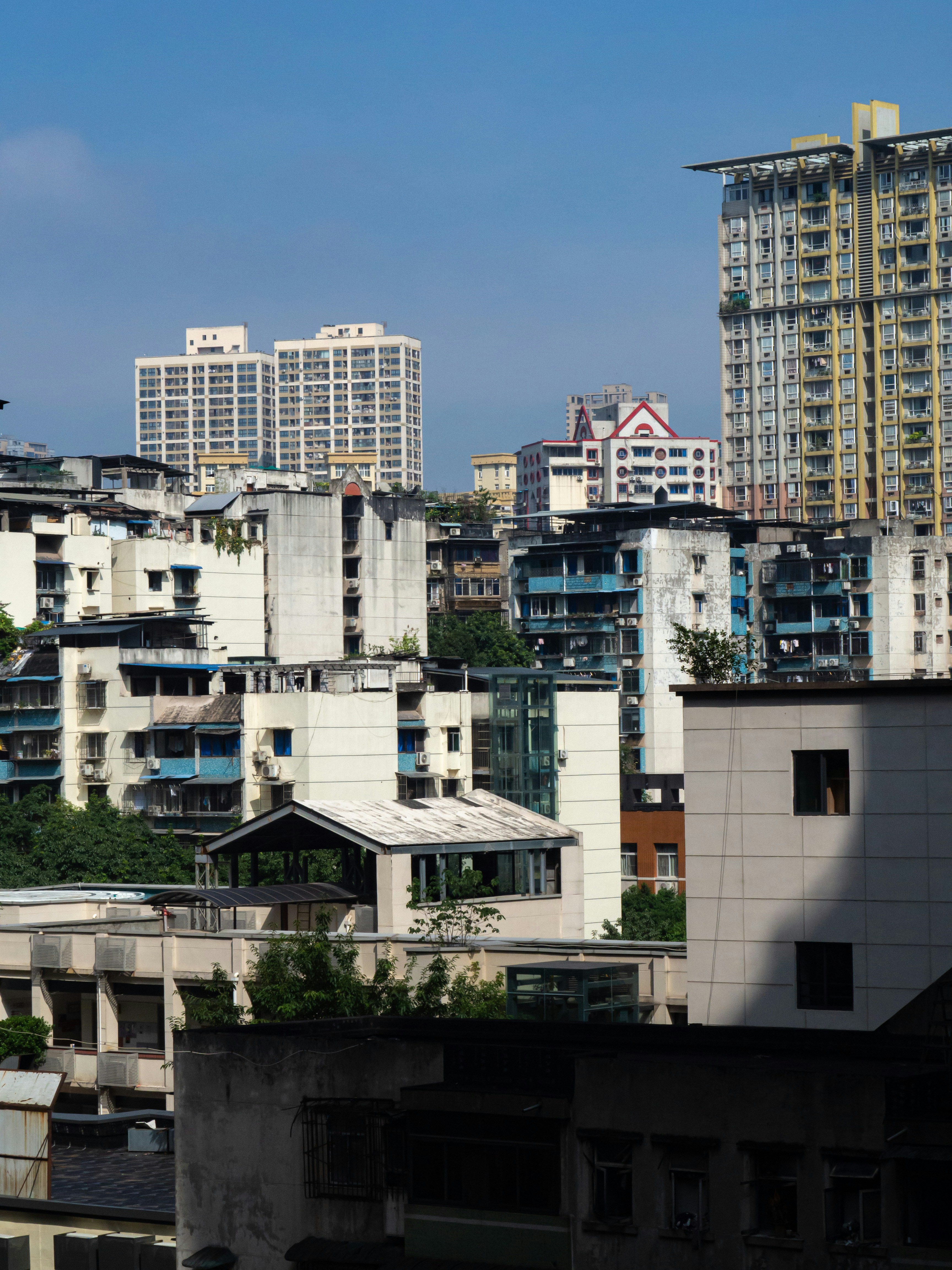OLYMPUS DIGITAL CAMERA | Dense urban cityscape with apartment buildings under blue sky.
