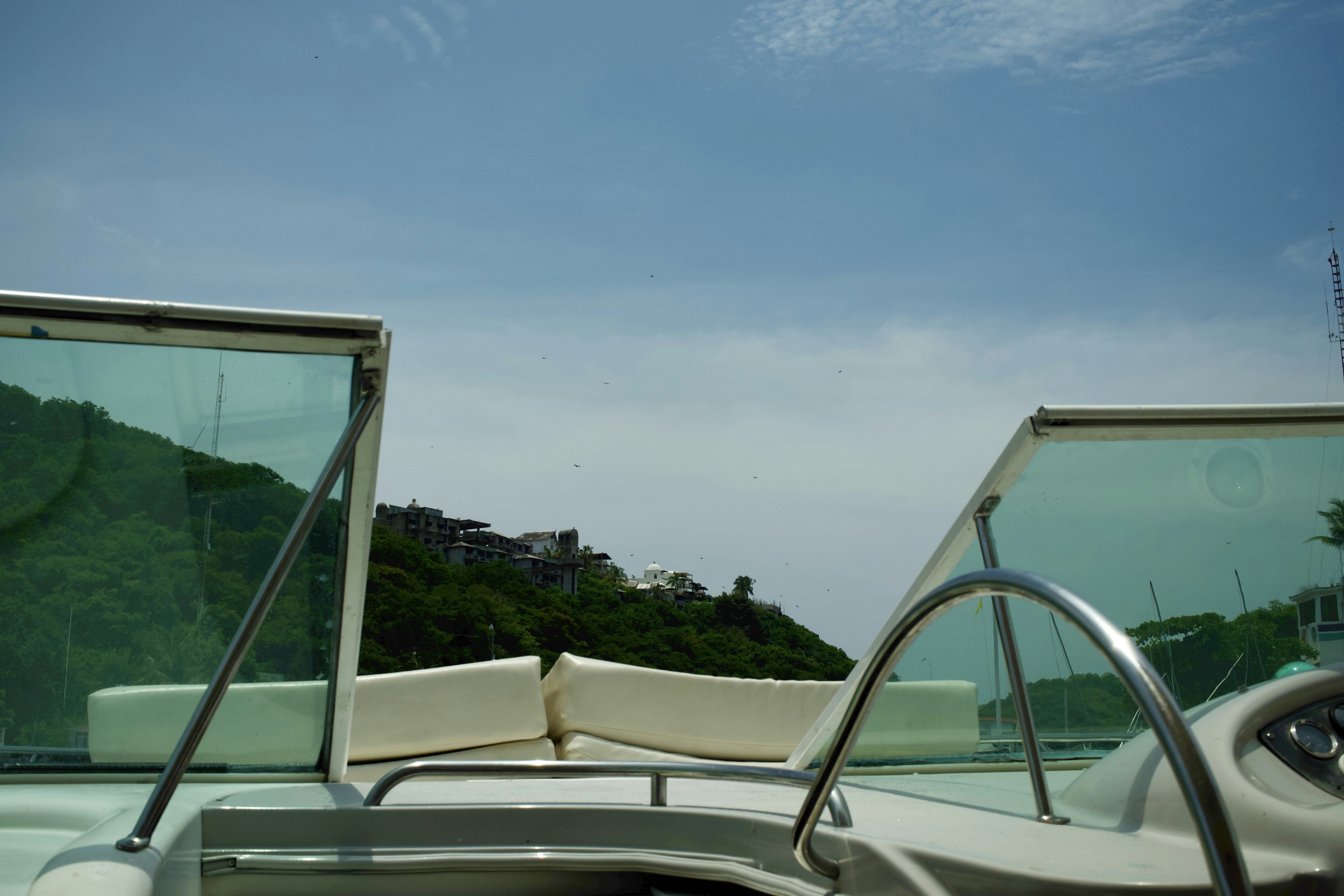 View from a boat looking towards a green hillside.