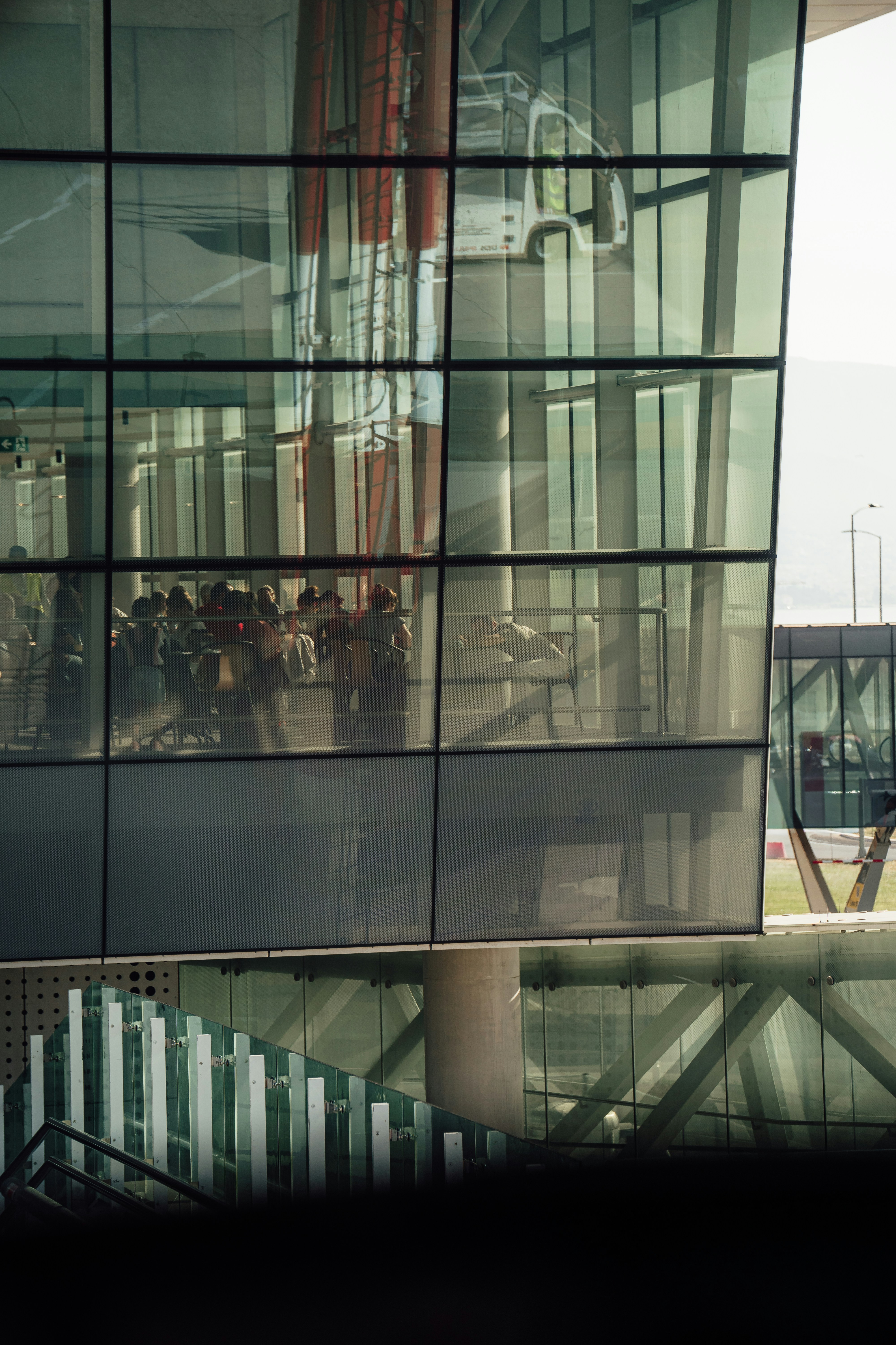 Reflection of people and vehicle in modern glass building