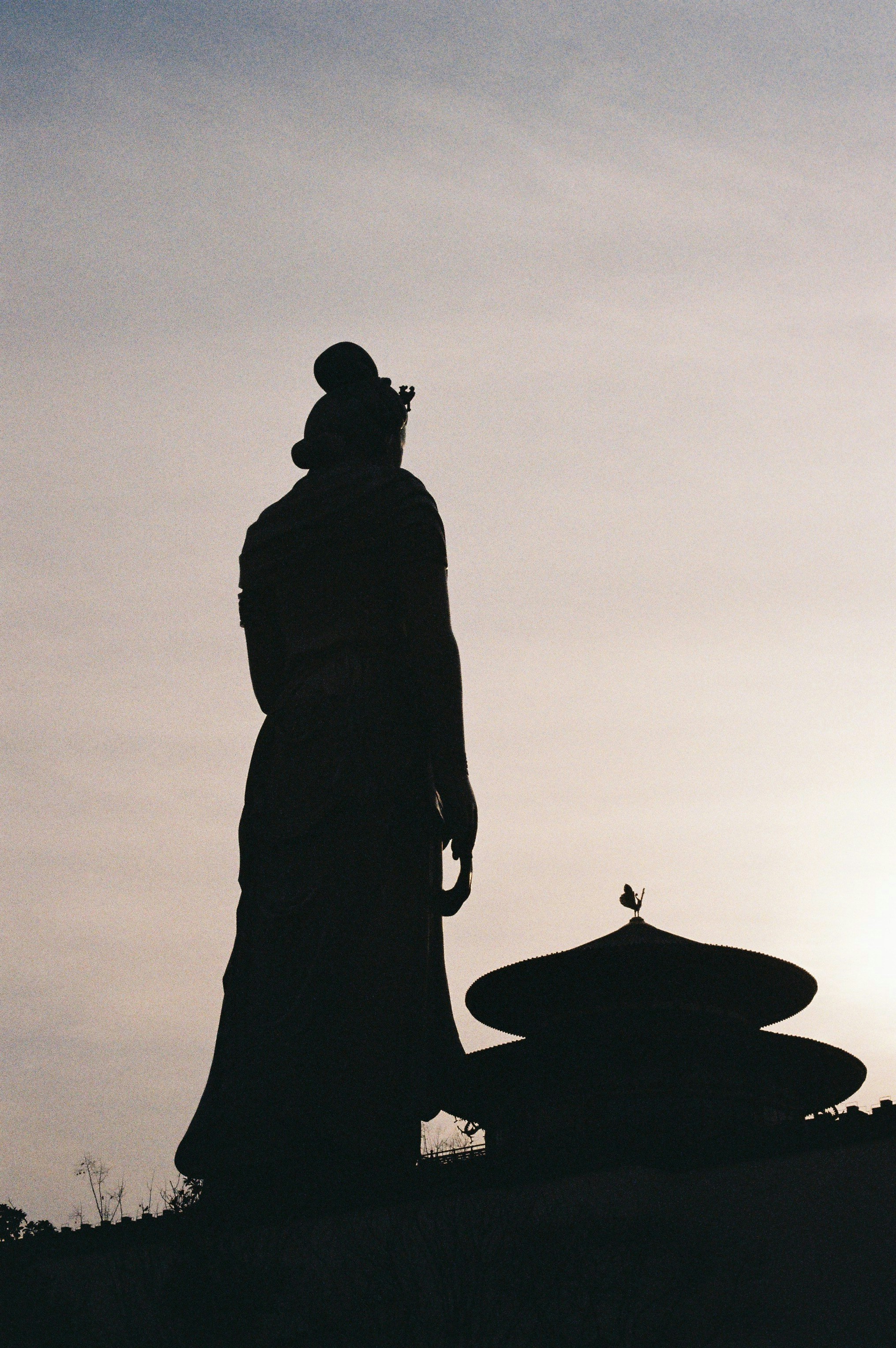 Silhouette of a statue against a pale sky