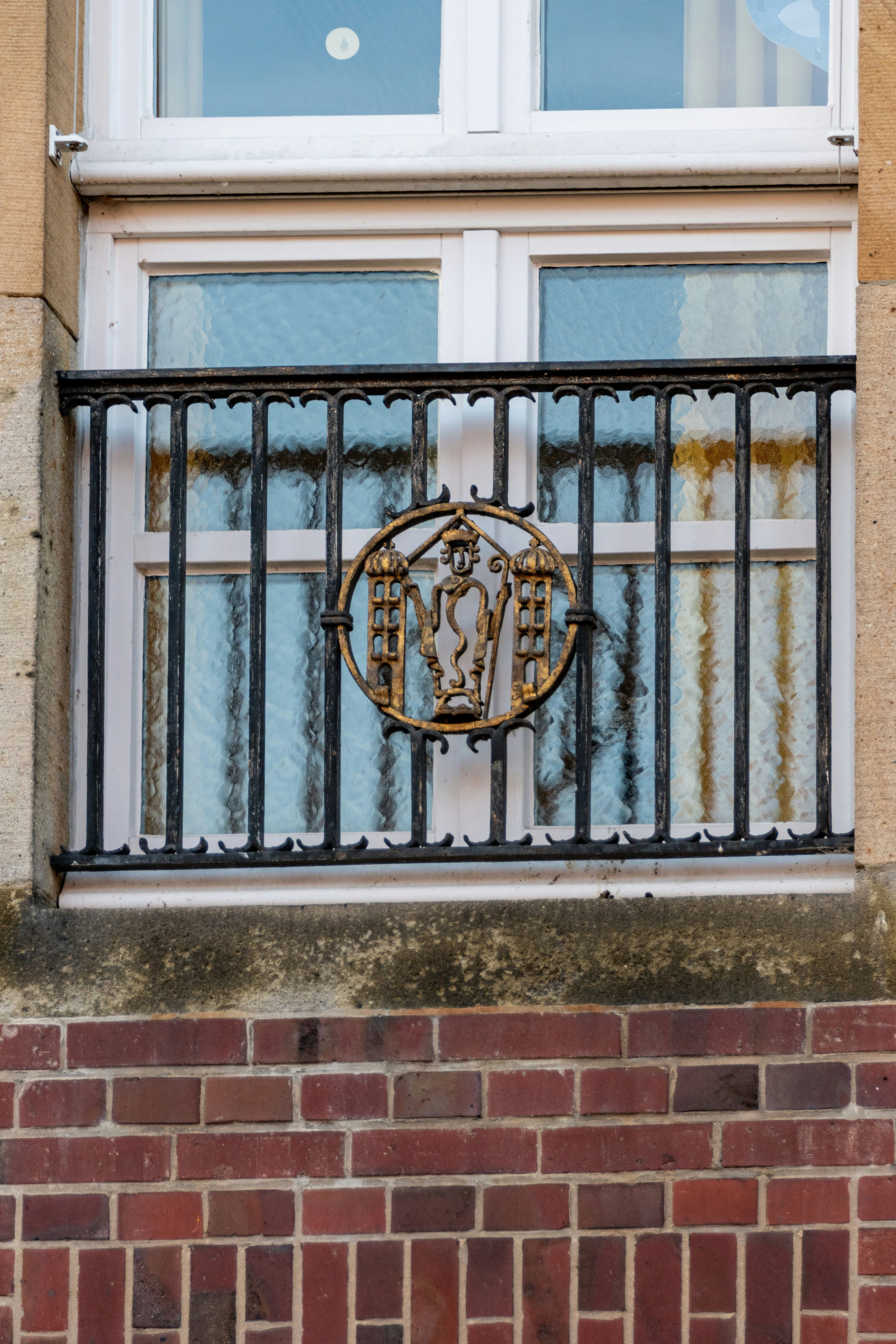 Rusting Crest Framed by Iron Bars on a Brick Facade