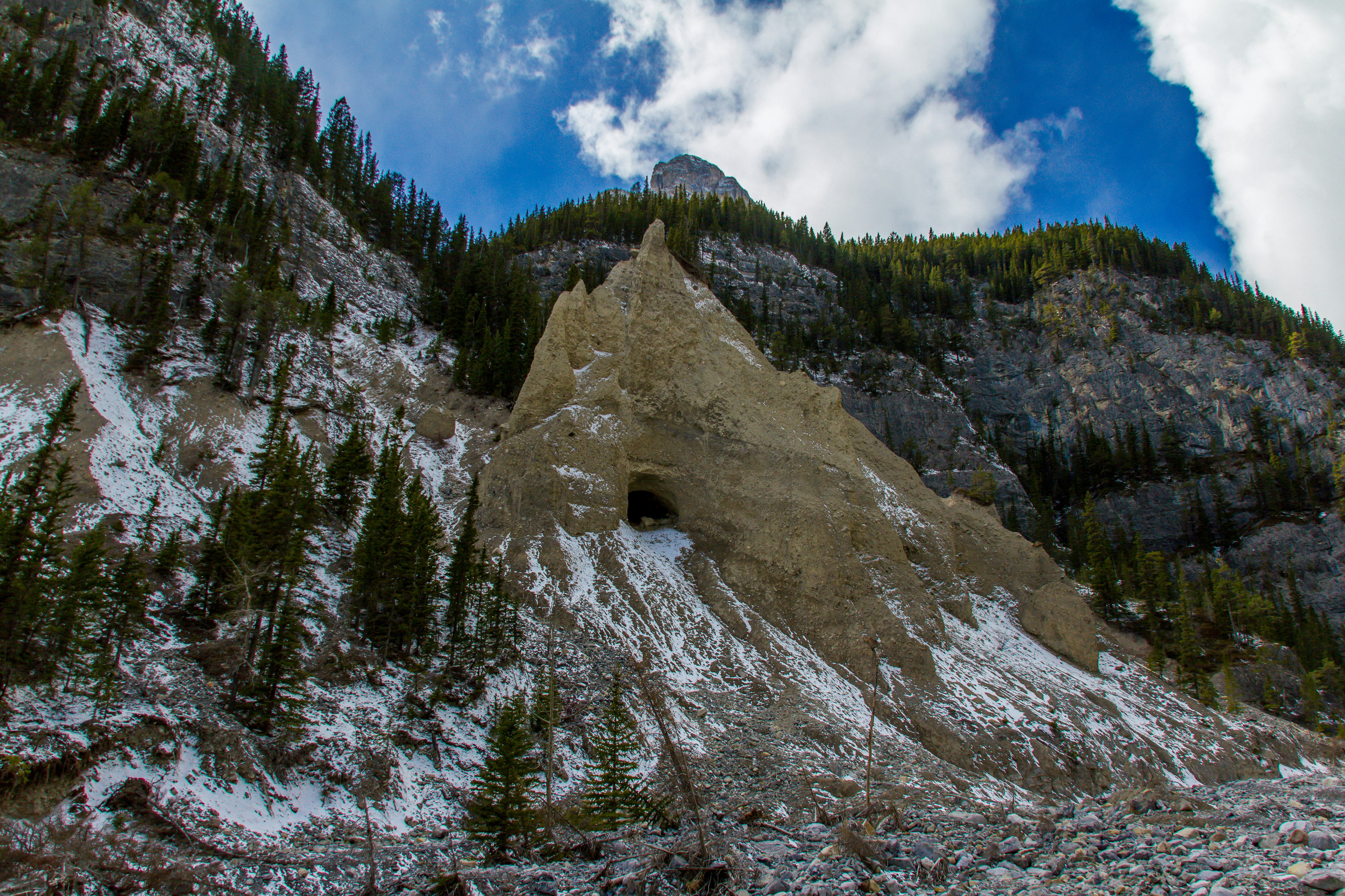 Hidden Cavern on a Snow-Kissed Cliff Beneath a Clear Alpine Sky