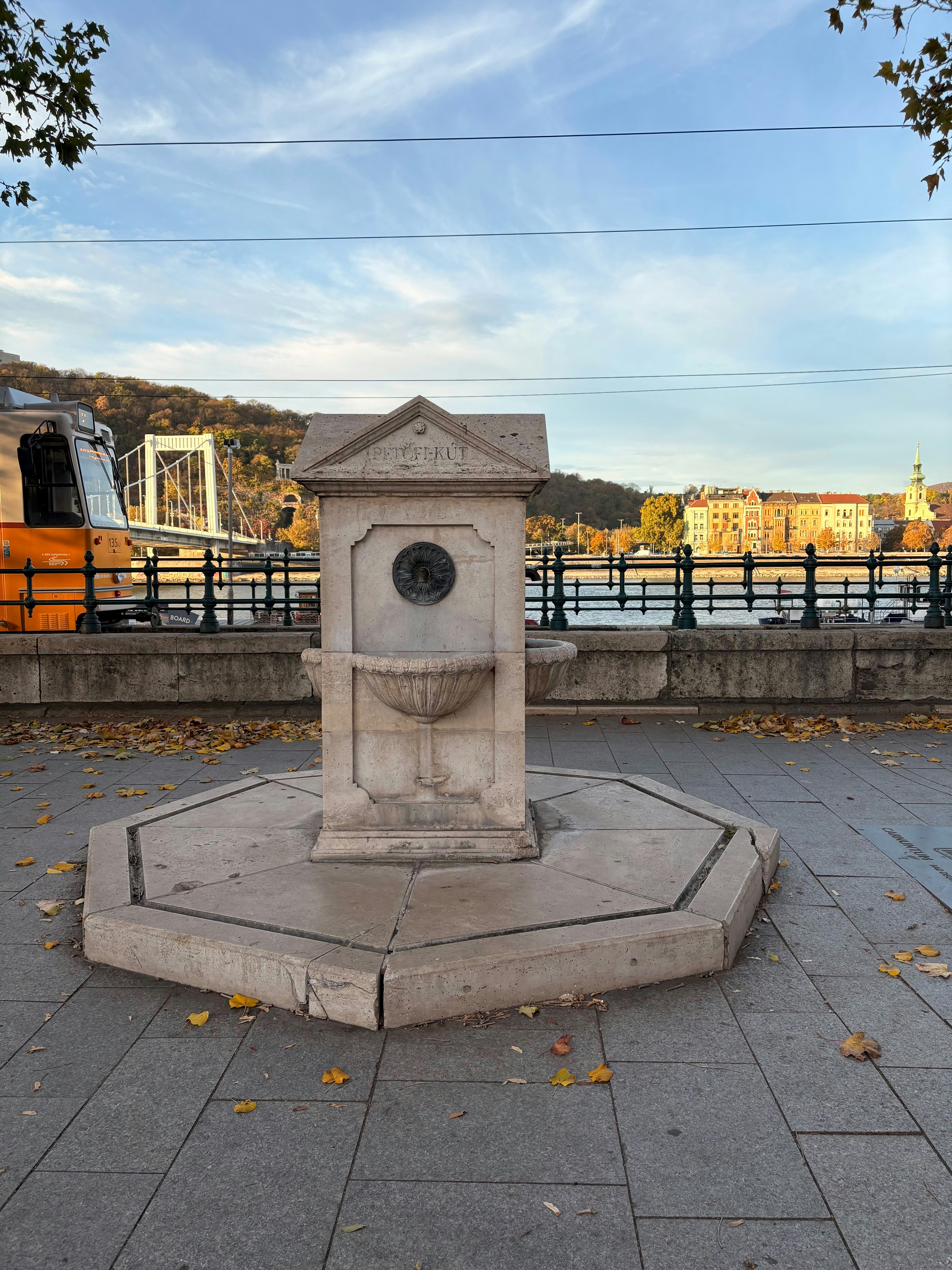 Stone fountain on a paved walkway near river