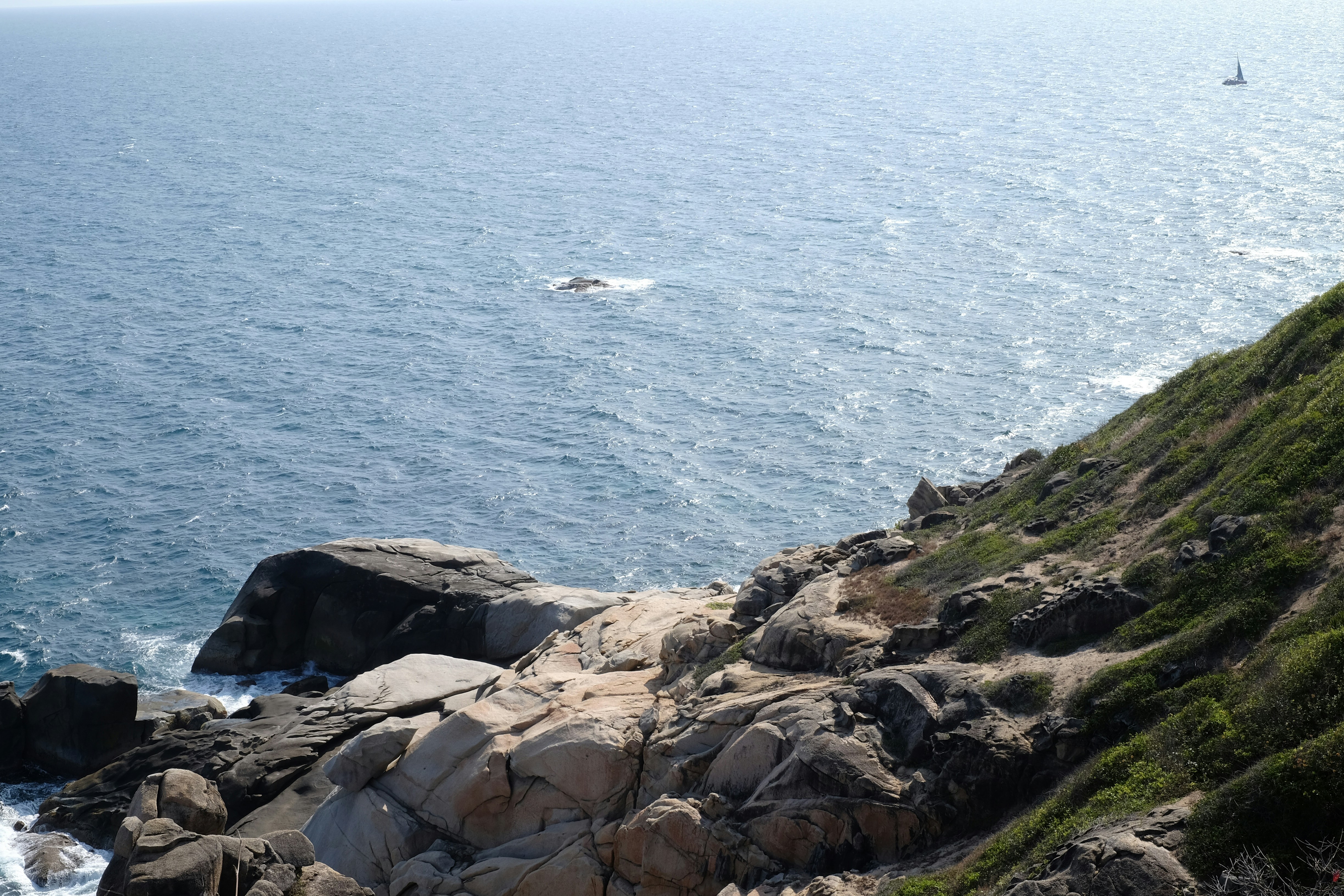Costa rocosa con océano azul y velero distante. foto – Imagen de Viajar ...