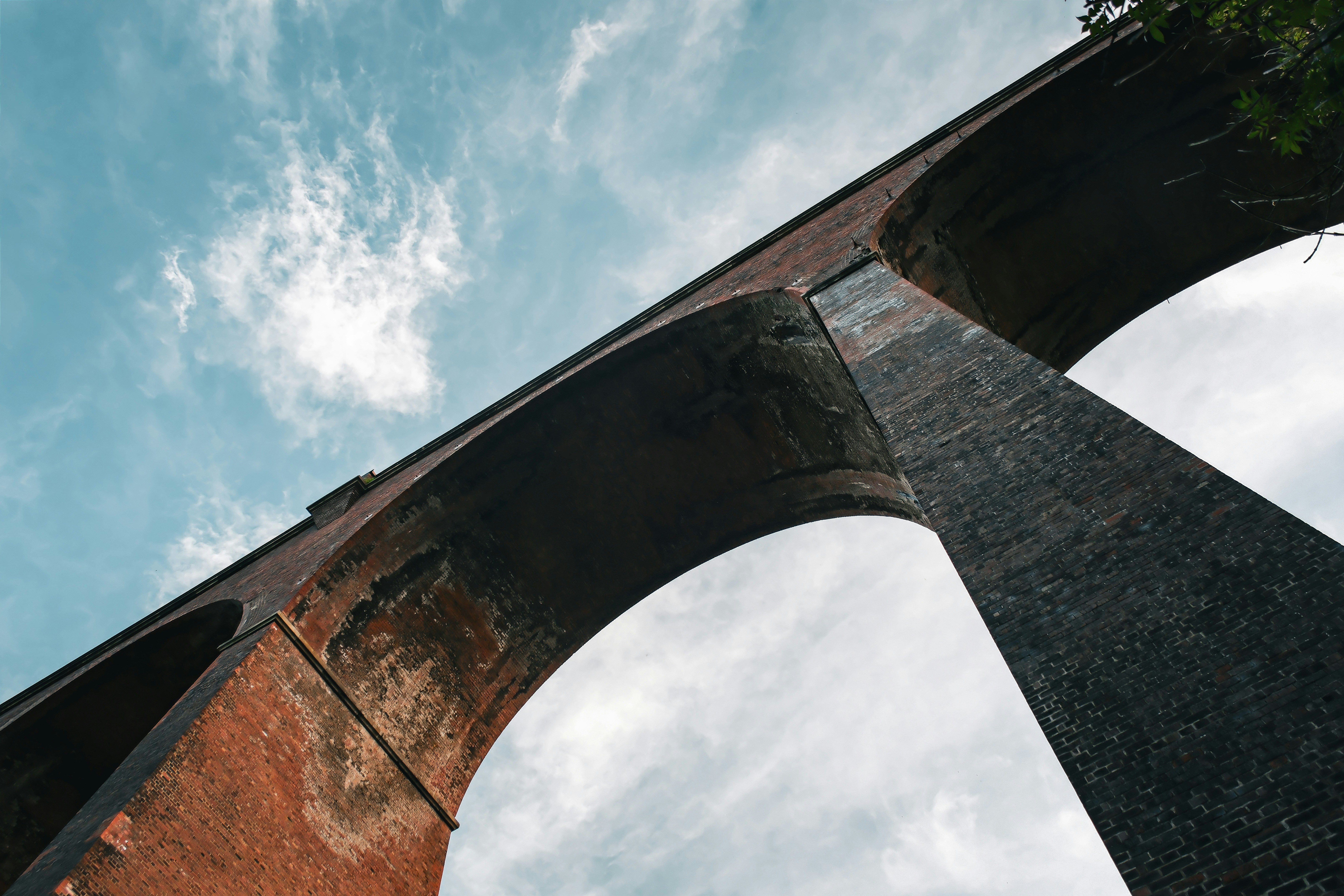 Historic brick viaduct with impressive arches, captured from a low angle | Looking up at a large brick viaduct against the sky