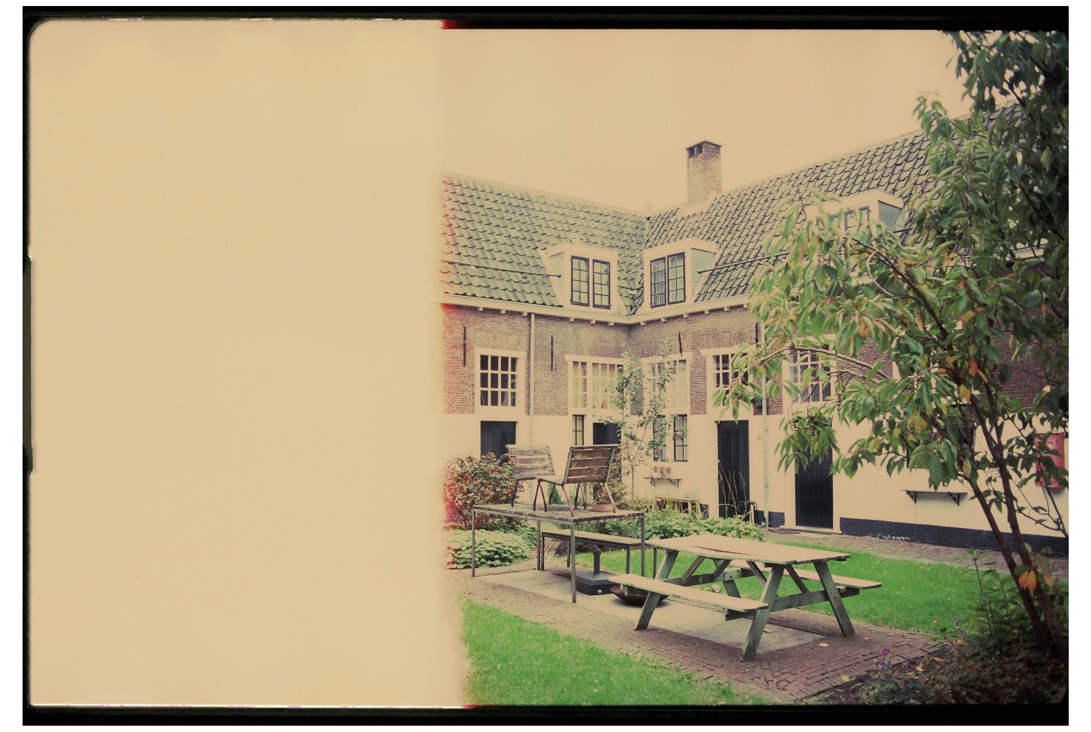 A serene courtyard featuring wooden benches and a lush garden, framed by charming architecture. The scene evokes a sense of nostalgia and tranquility.