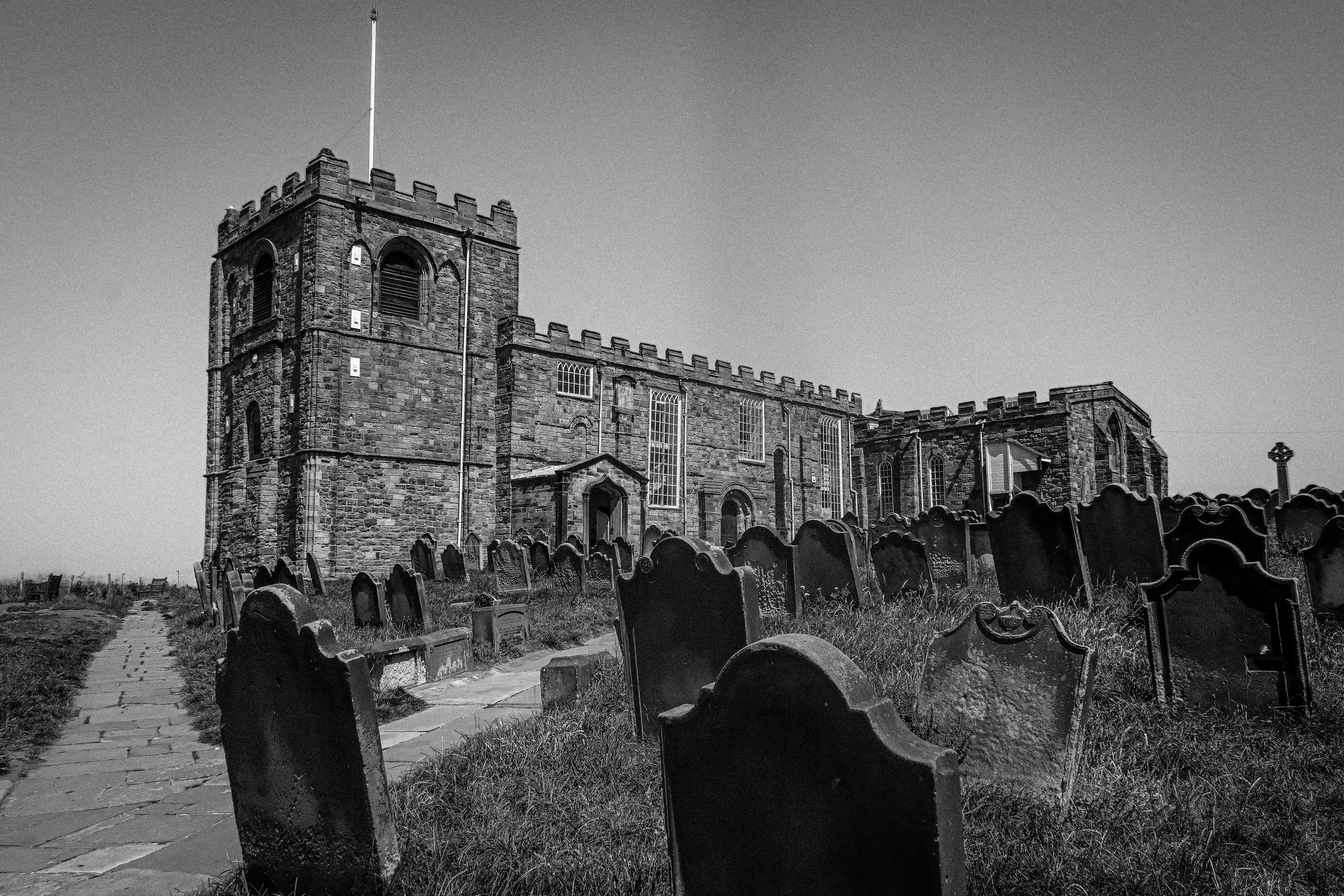 Old stone church with a historic graveyard. | Historic stone church with graveyard under a clear sky
