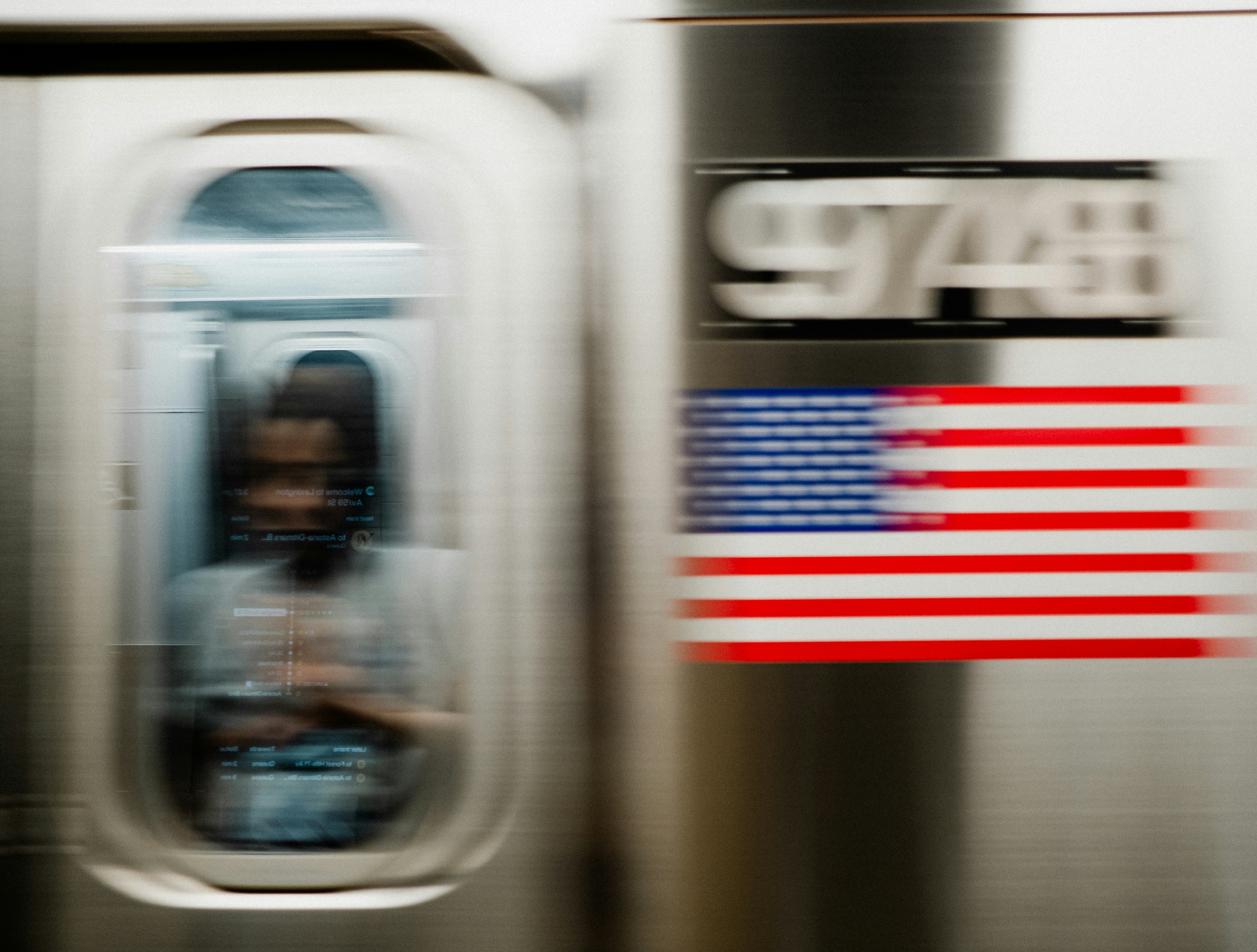 I call this Still in transit: a study of how digitalization in an era of hyperspeed can make us humans blurry. | Man inside moving train with american flag