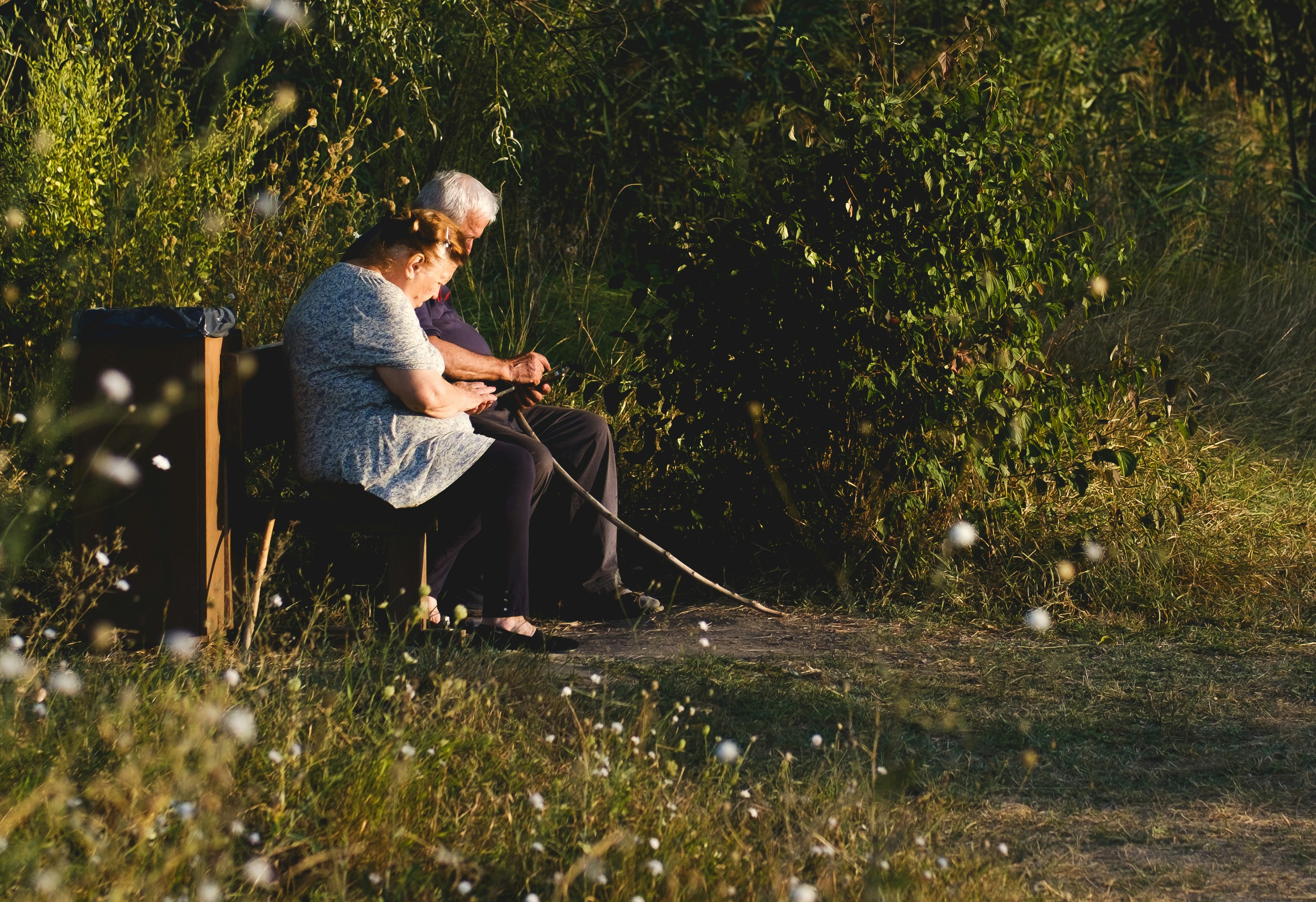 Elderly couple sitting on a park bench together.