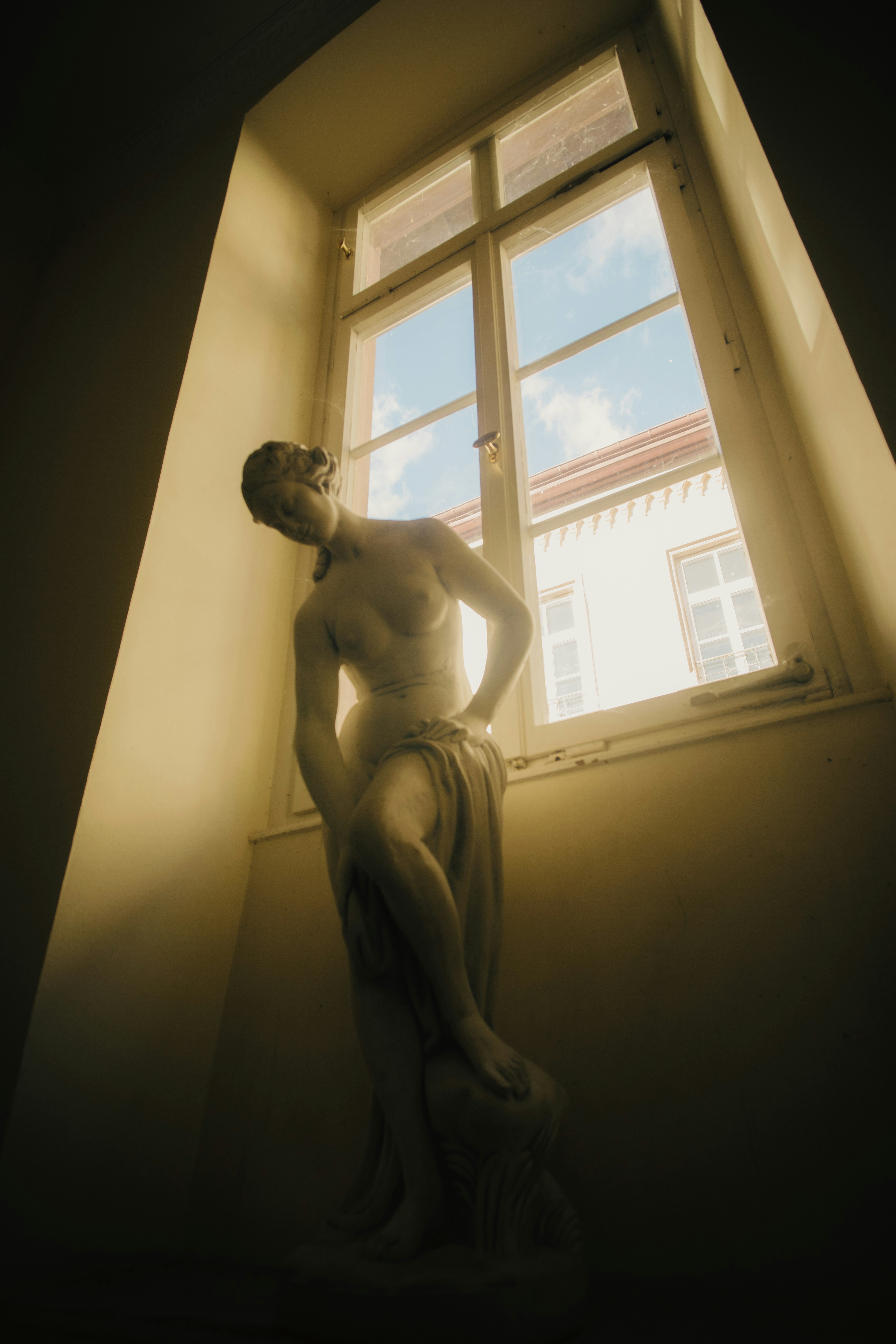 Marble statue of a woman near a window.