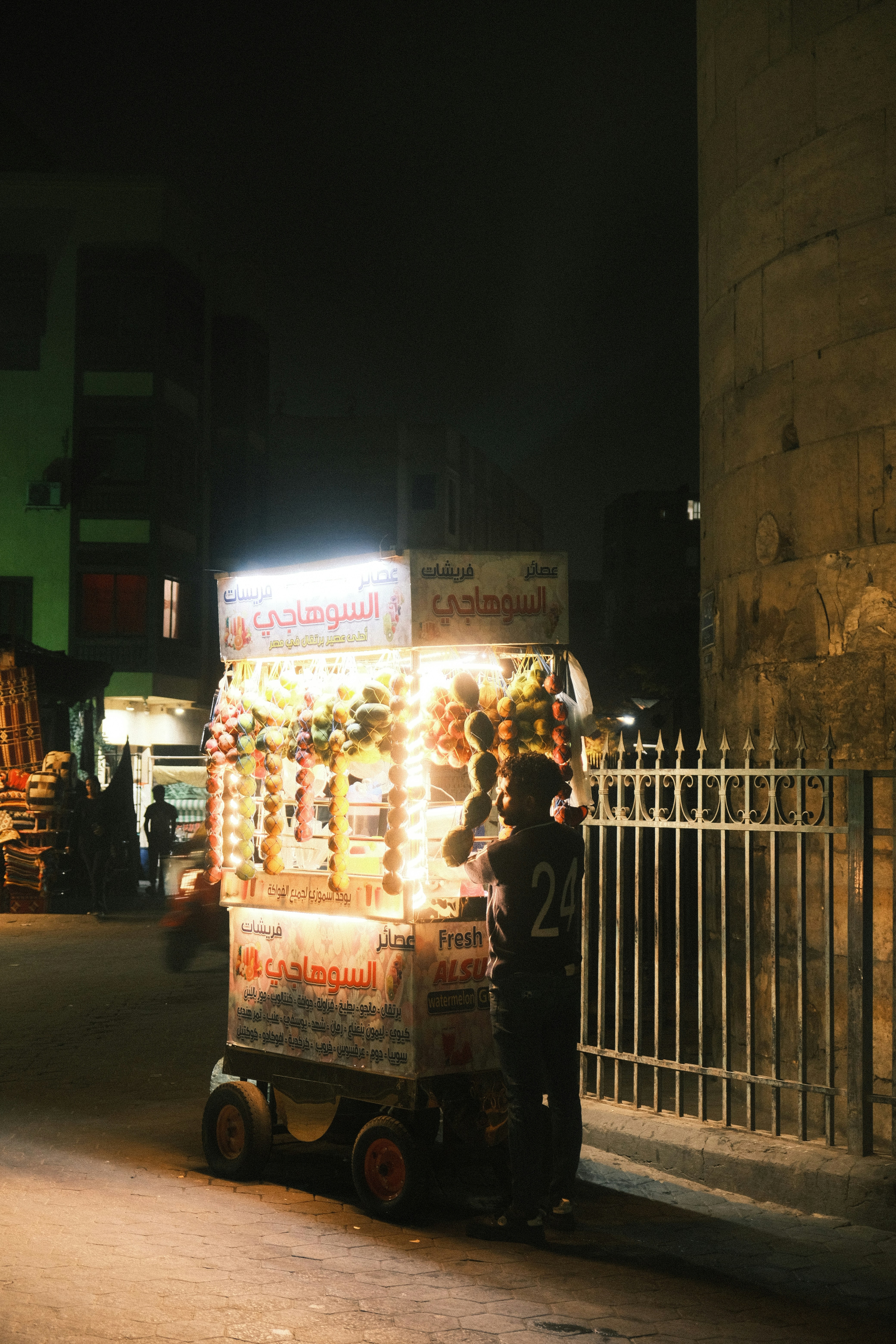 a salesman on el moez street, Cairo, Egypt | Man standing by illuminated fruit stand at night