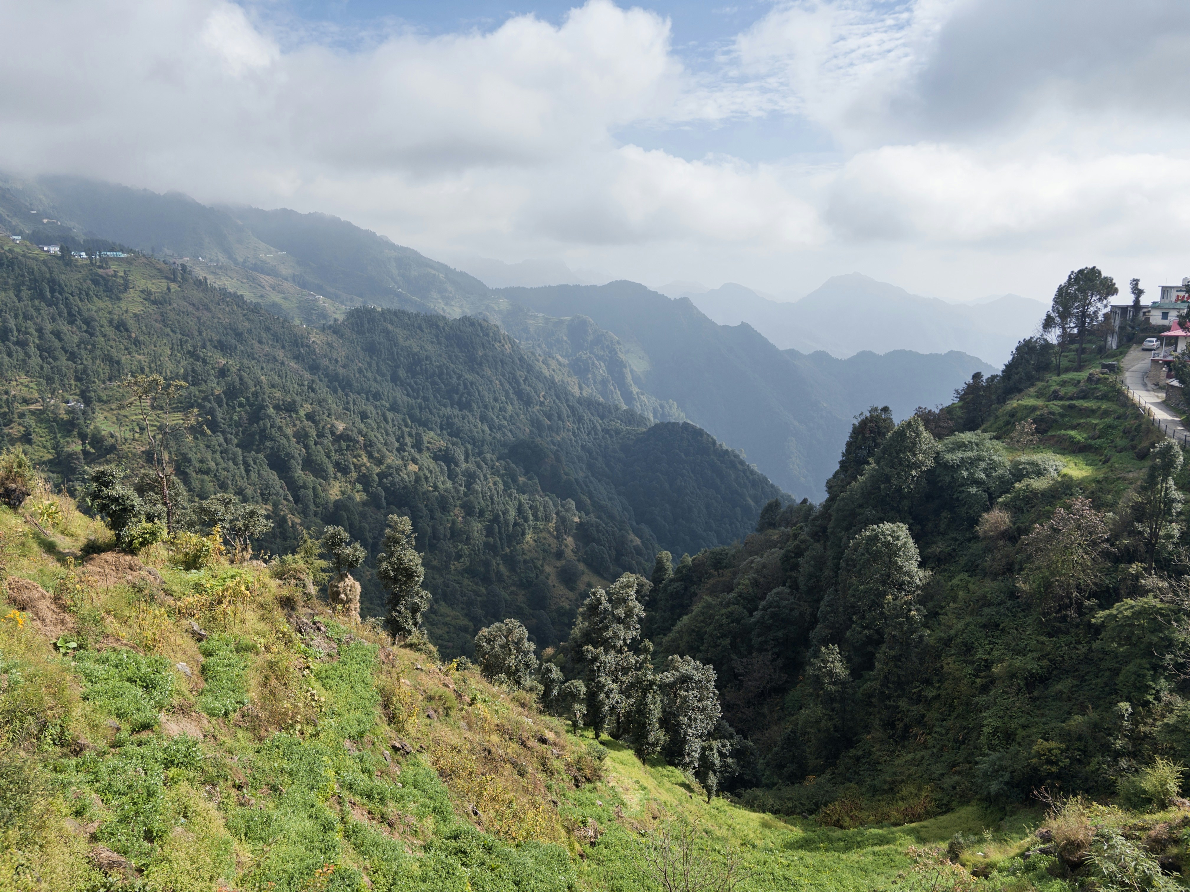 Lush green mountains with scattered clouds on a bright day.