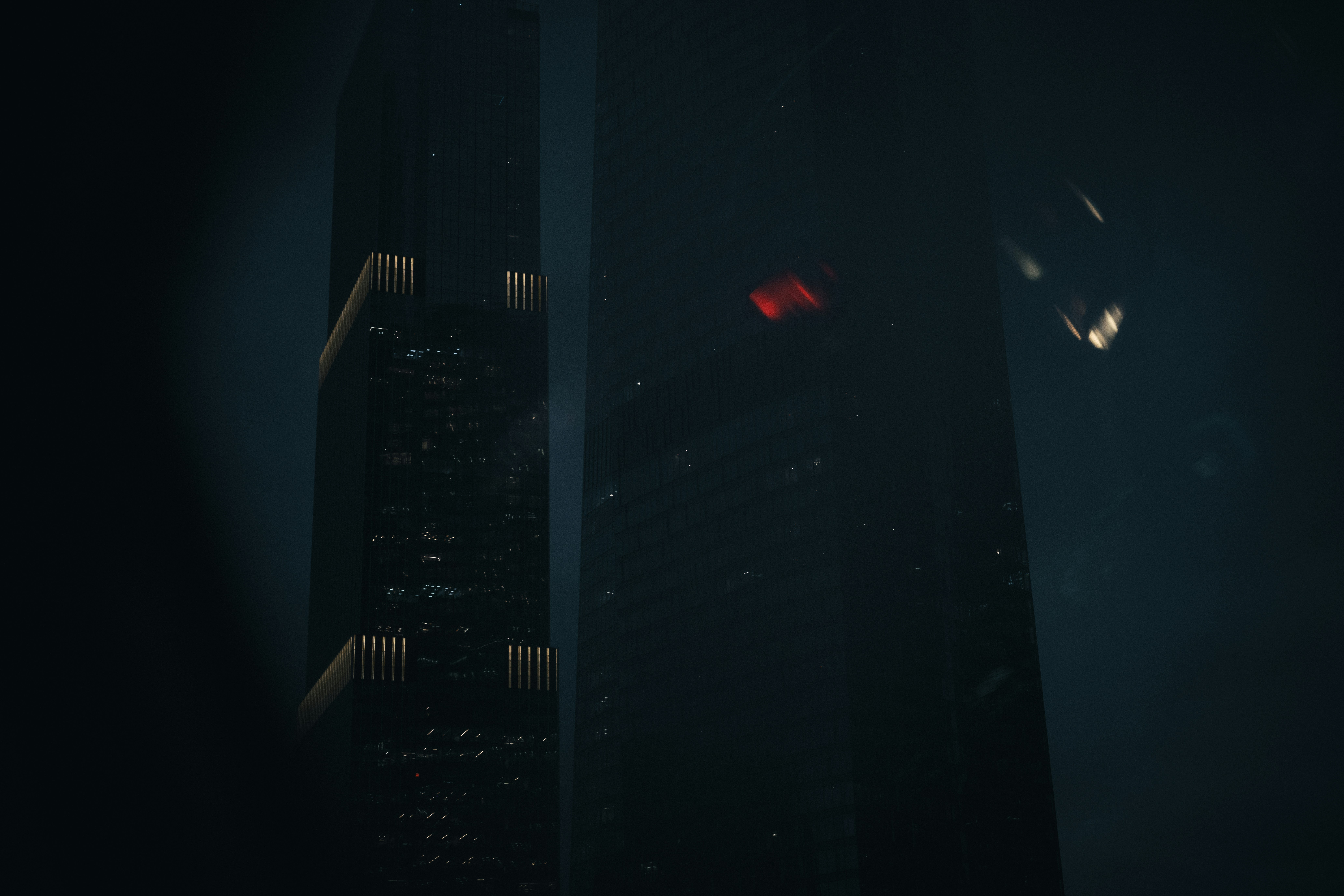 Dark skyscraper at night with illuminated windows.