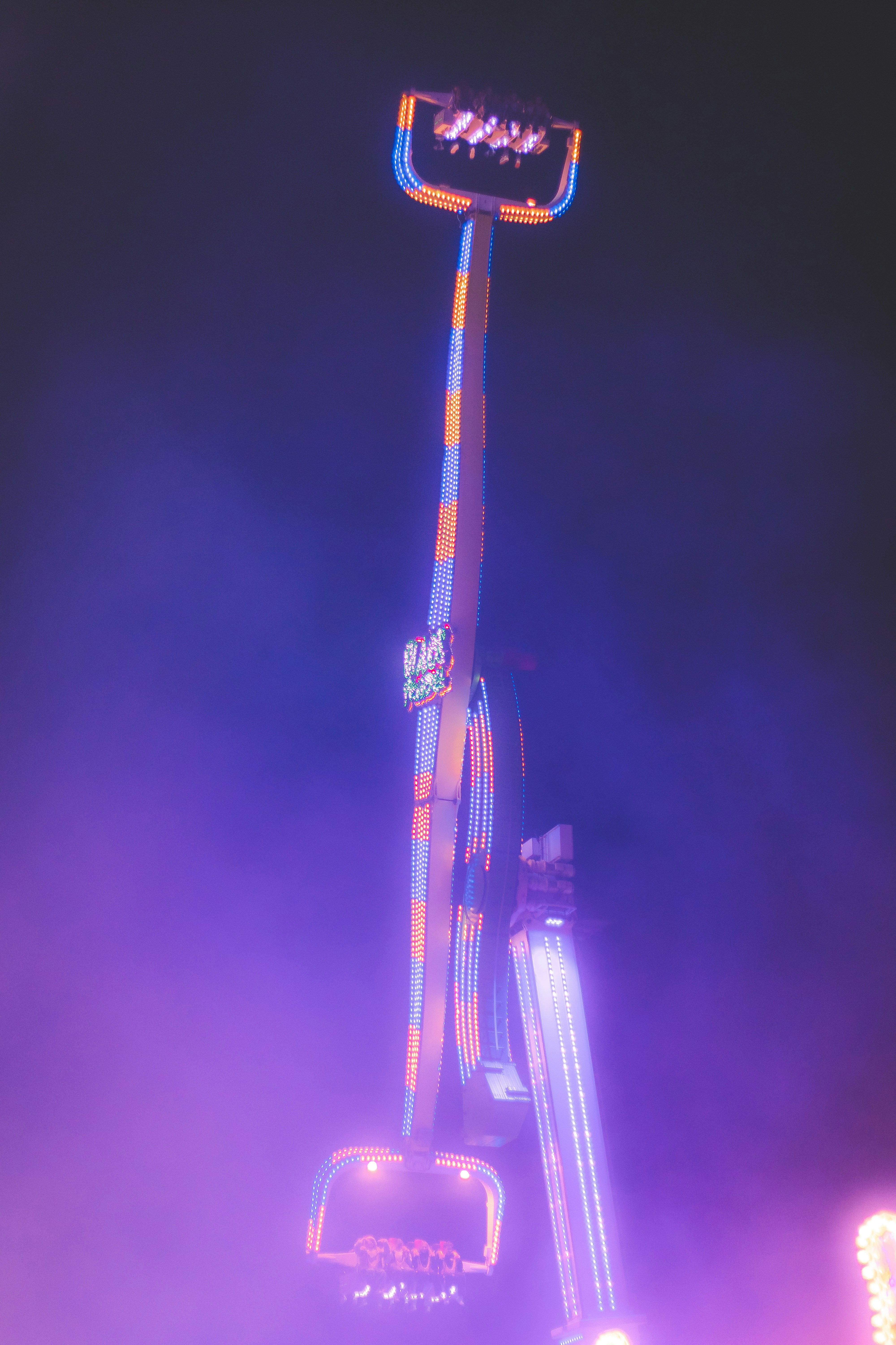 Neon Nightlift: A Luminescent Tower Slicing Through Purple Fog