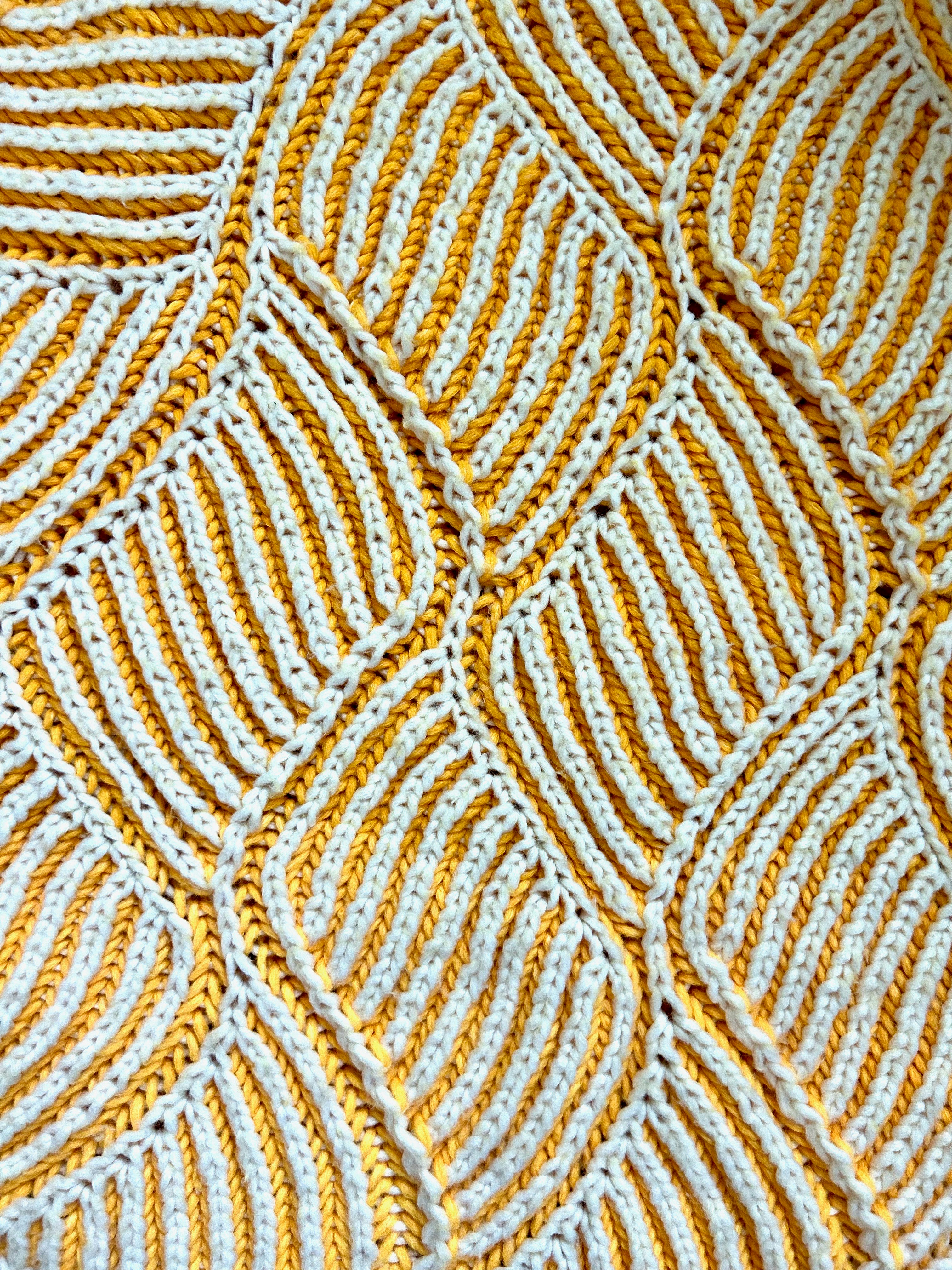 Intricate textile pattern featuring interwoven yellow and white threads in a geometric design.