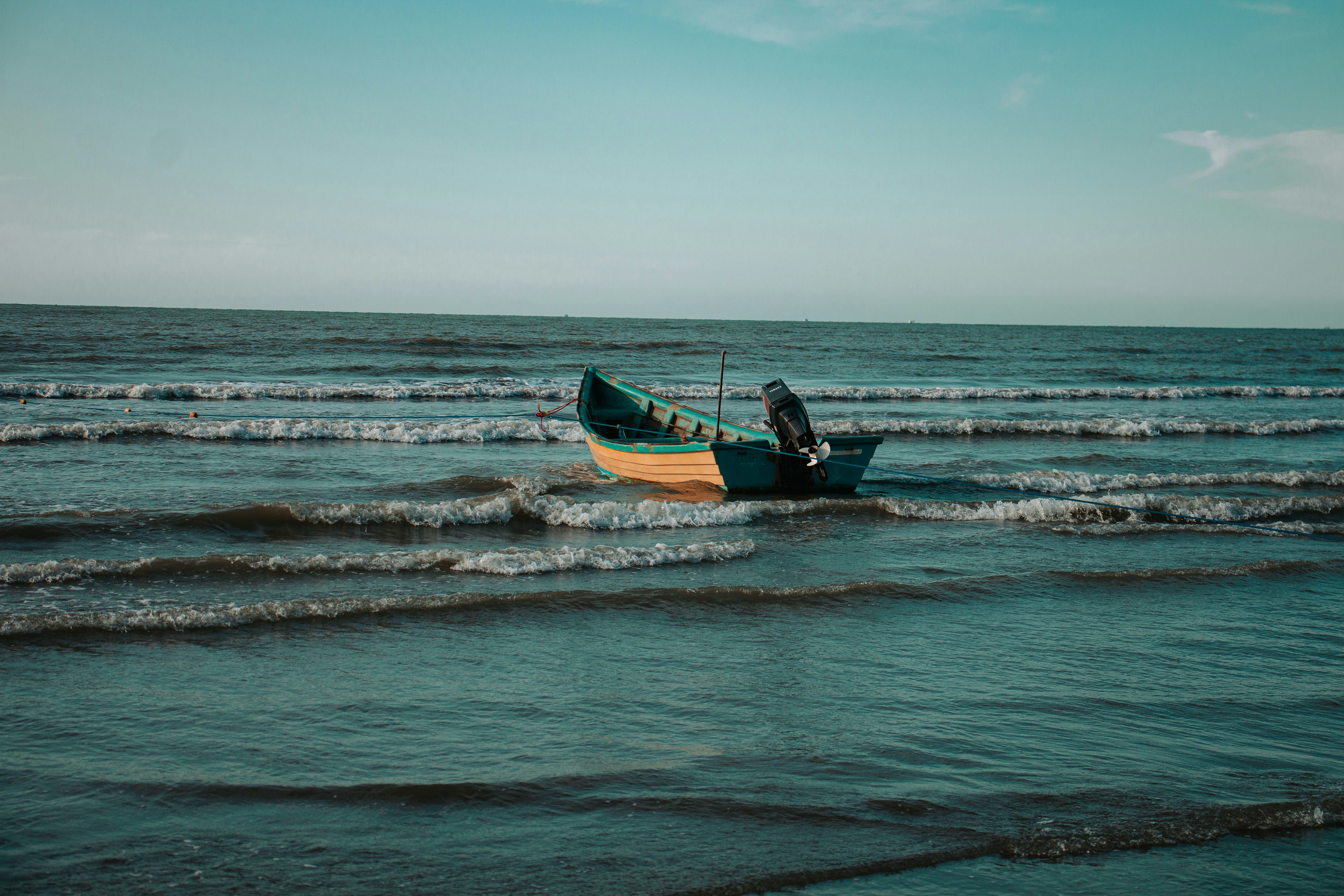Farahabad Beach — where the waves tell everyday stories. ساحل فرح‌آباد، جایی که موج‌ها از روزمرگی حرف می‌زنن. | A small boat floats on the ocean waves.