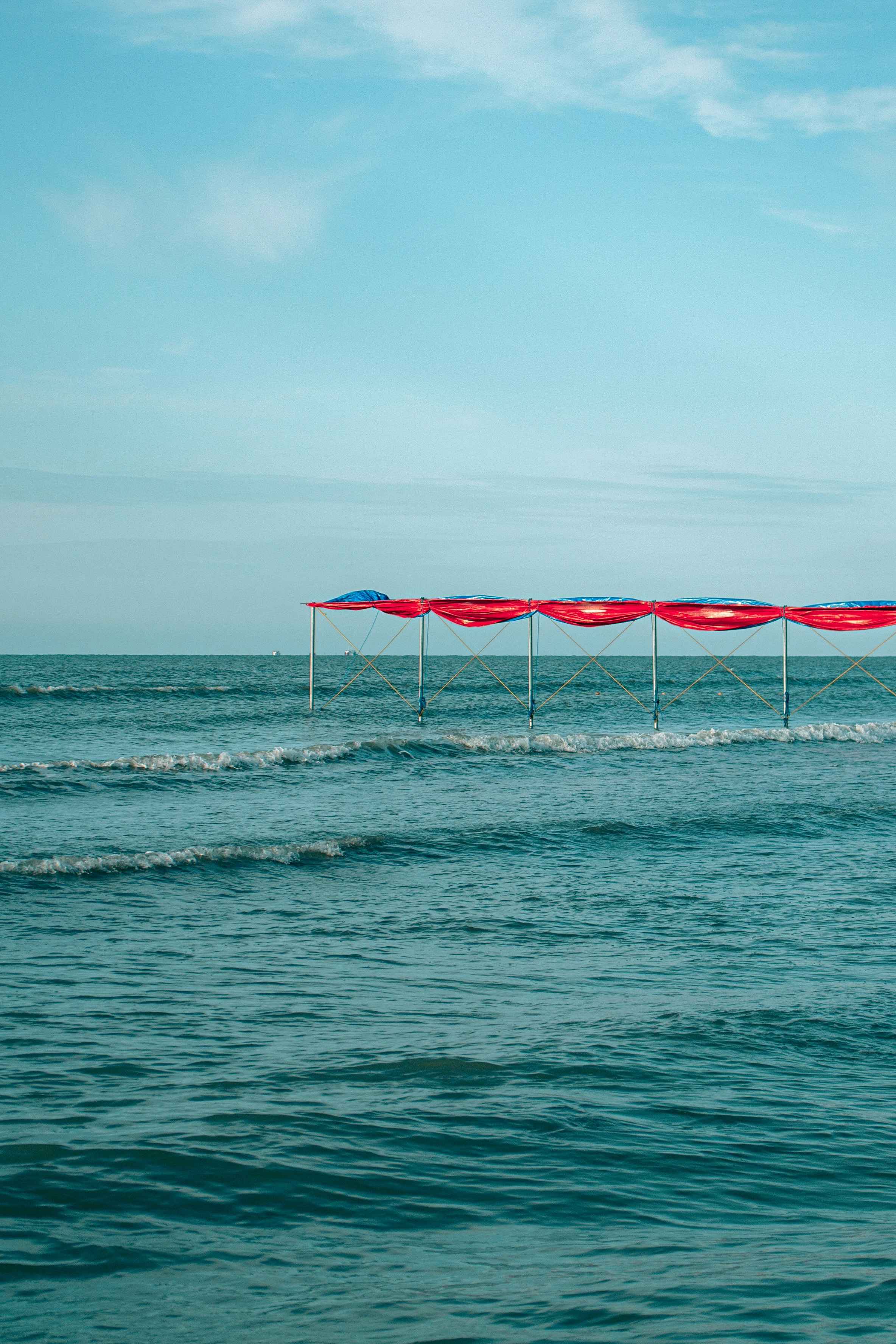Red Canopy Horizon: A Quiet Pier Edged by Turquoise Swells
