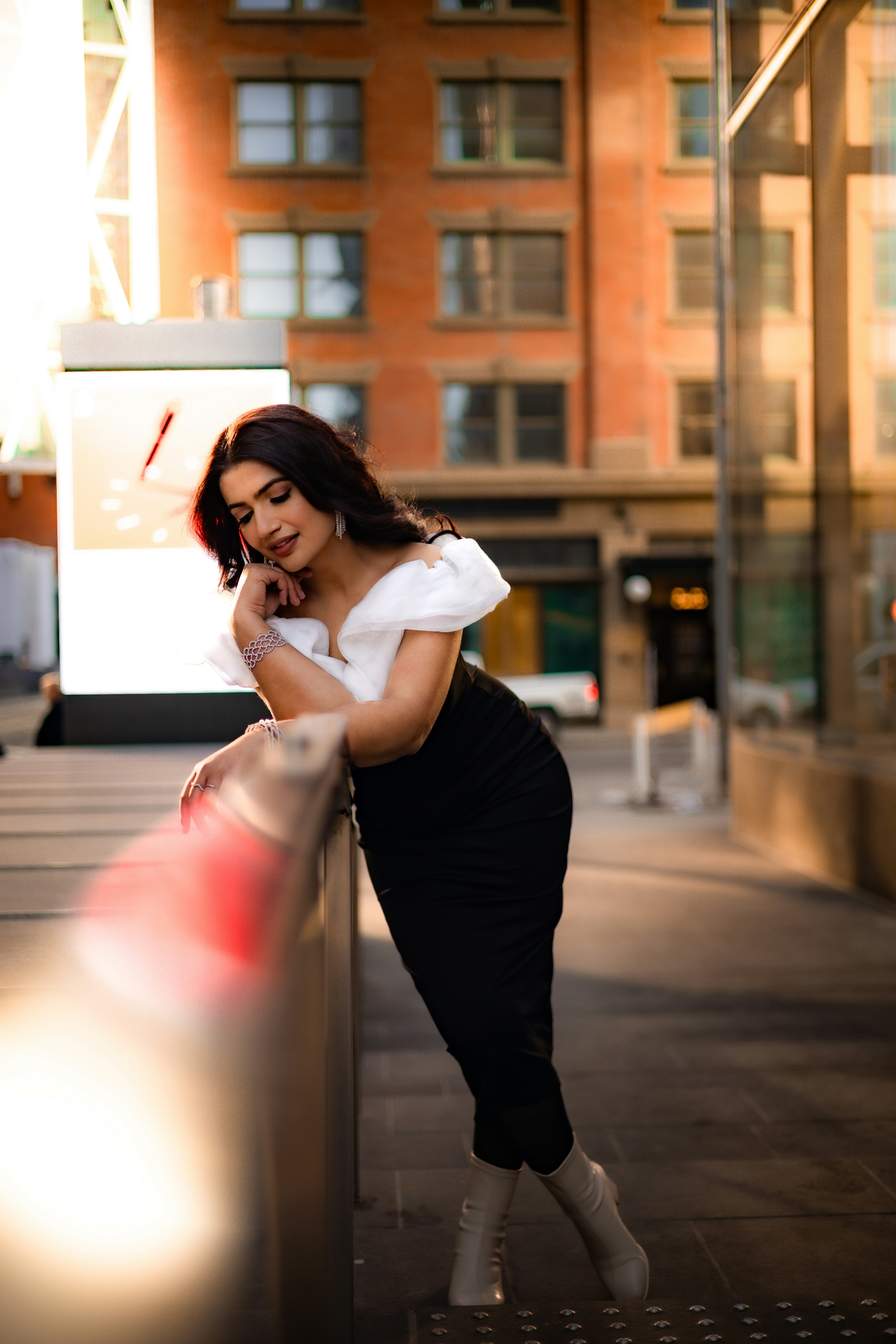 Woman in white top and black skirt leaning on railing.