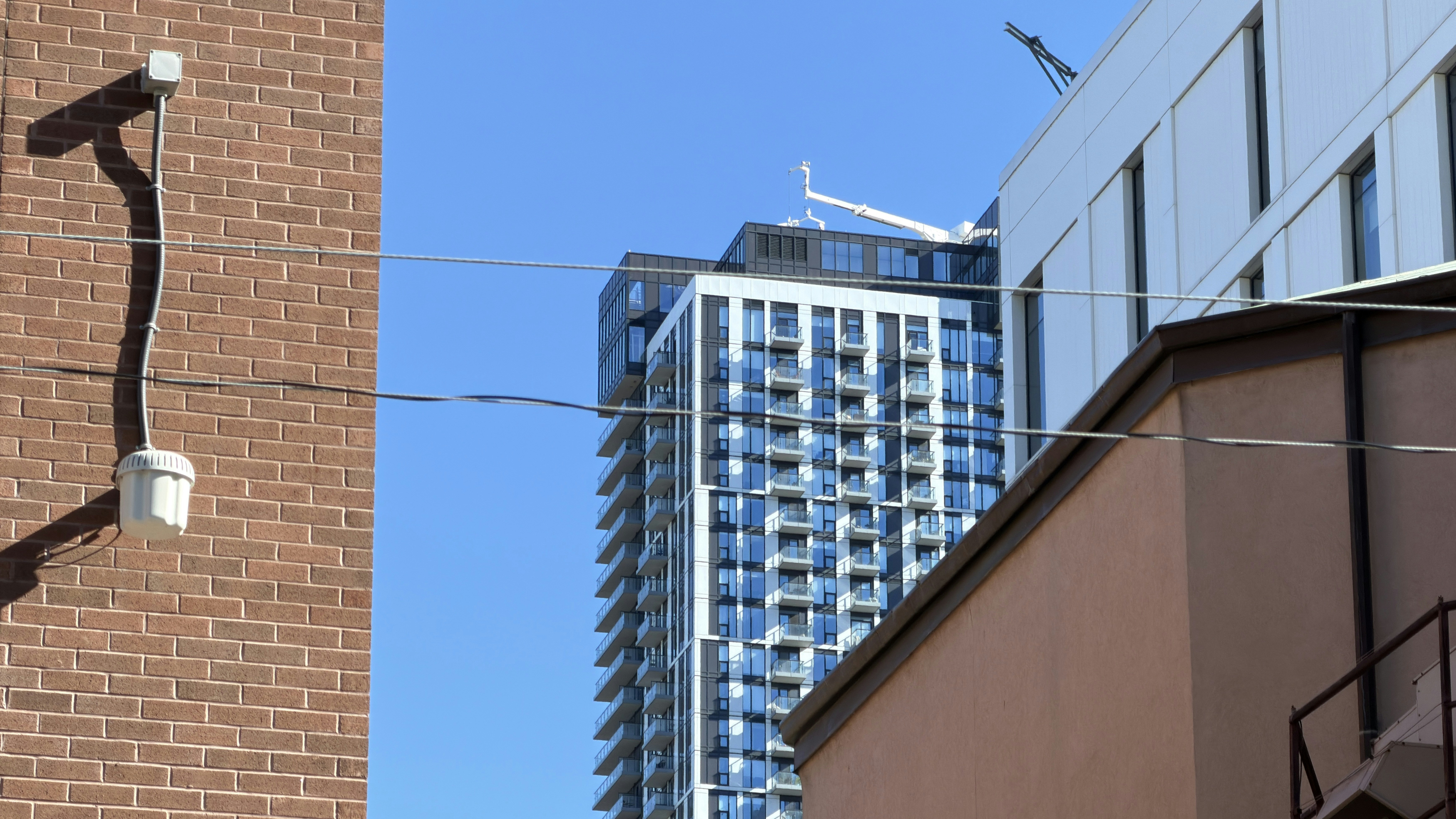 Blue-Sky Geometry: Cranes Framing a Glass-Fronted Tower
