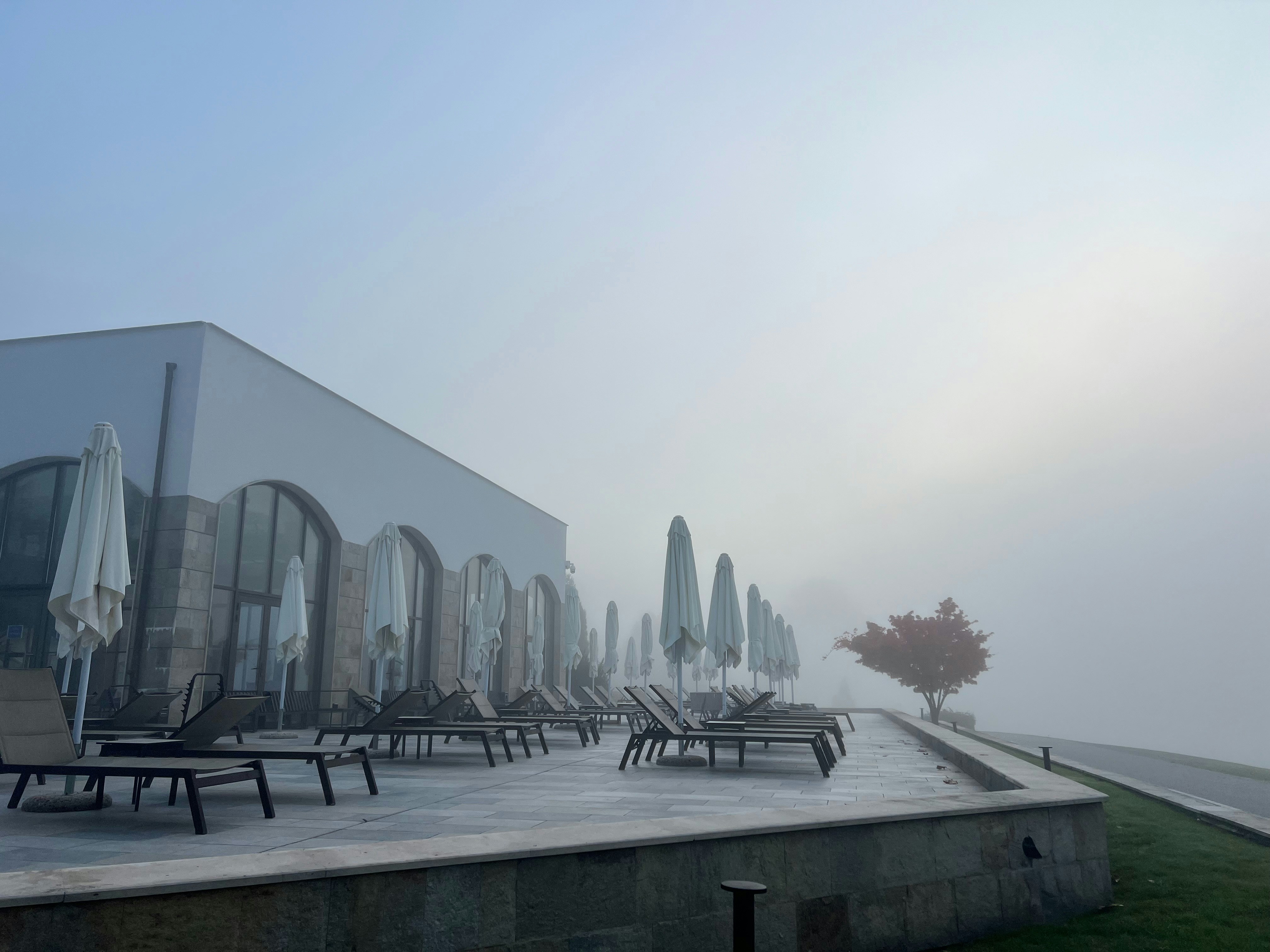 Relax and unwind in the sky | Lounge chairs on a foggy patio next to a building.