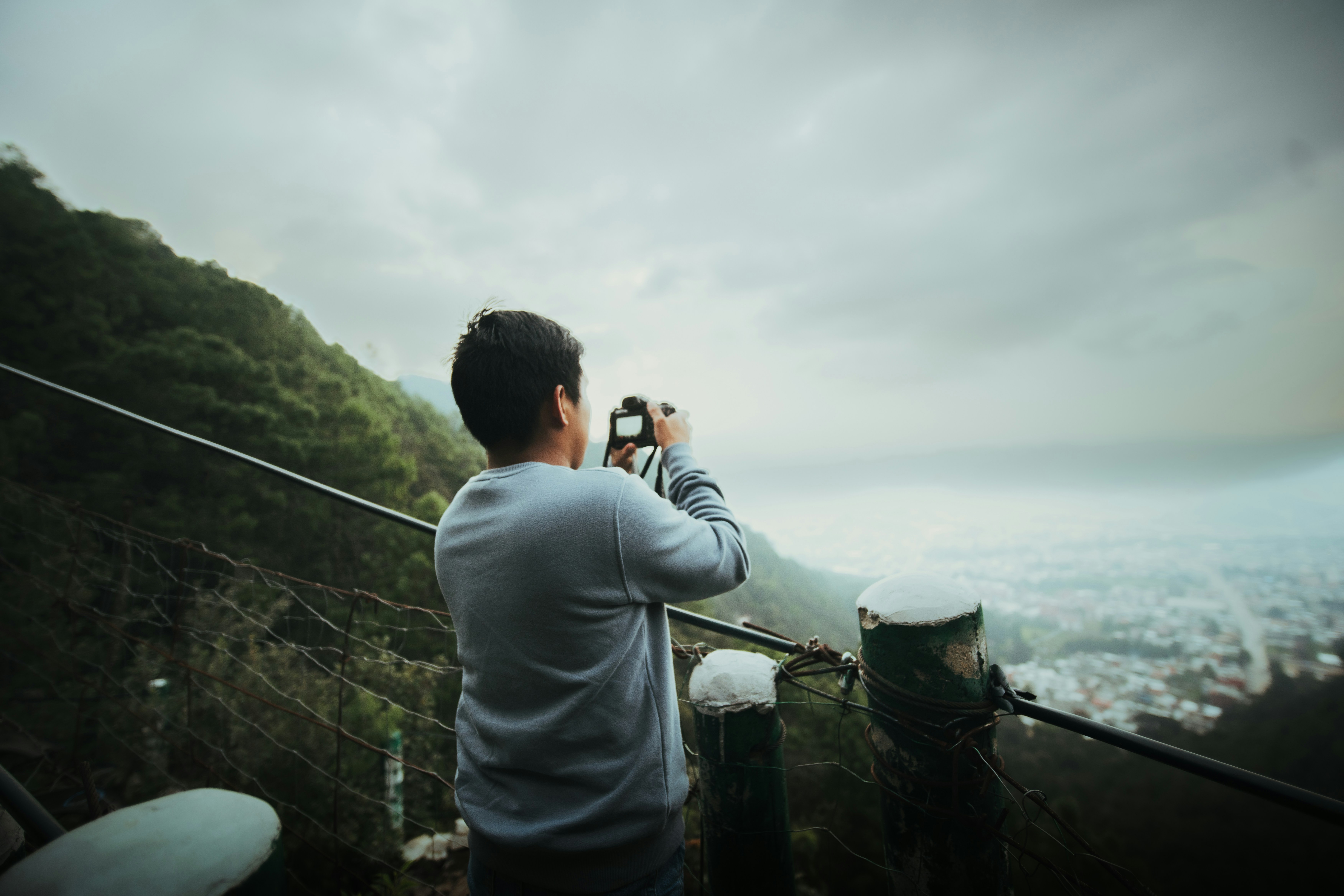 Man taking a picture of a cloudy cityscape view.