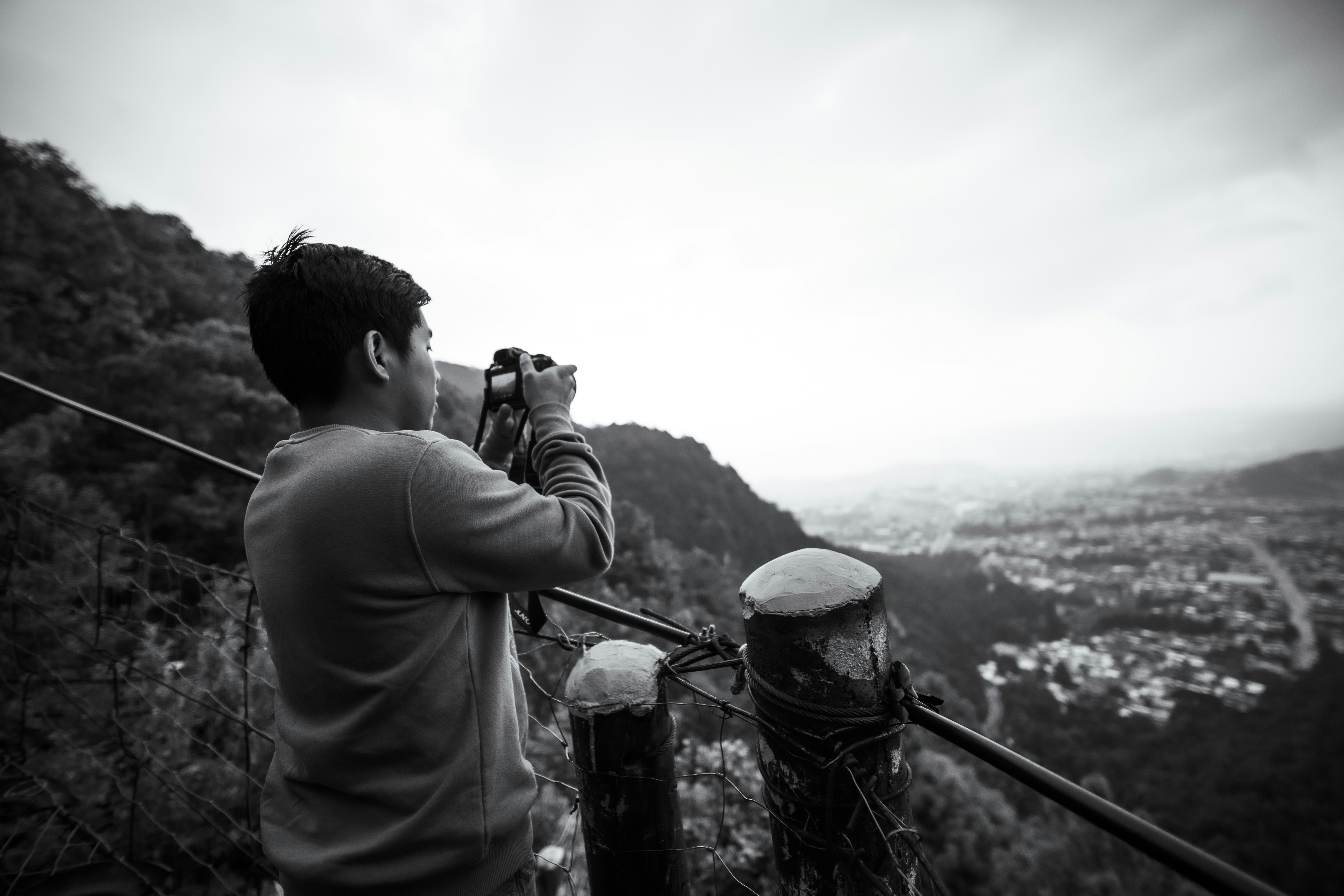 Man taking a picture of a city from a hill.