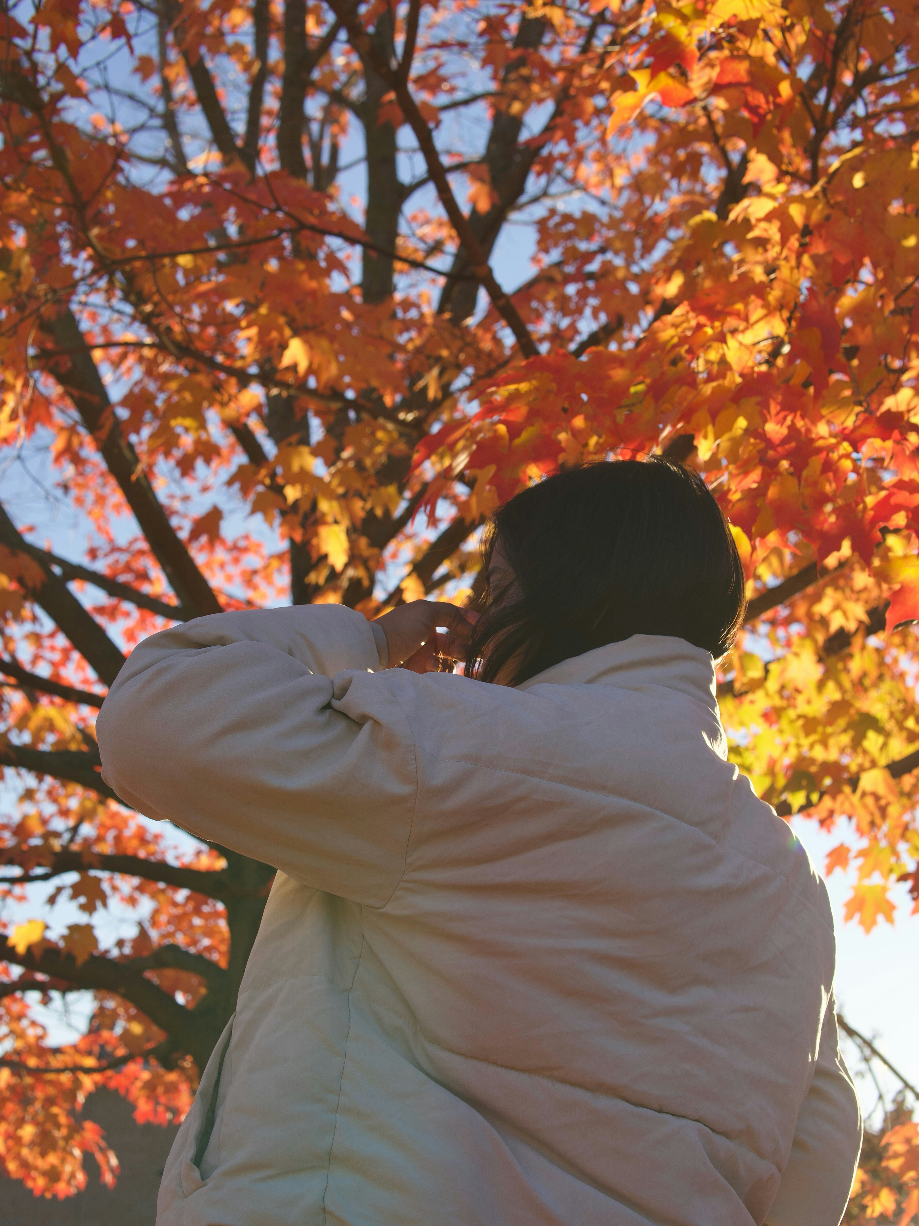 Individual in a white jacket surrounded by vibrant autumn leaves, capturing the essence of the season.