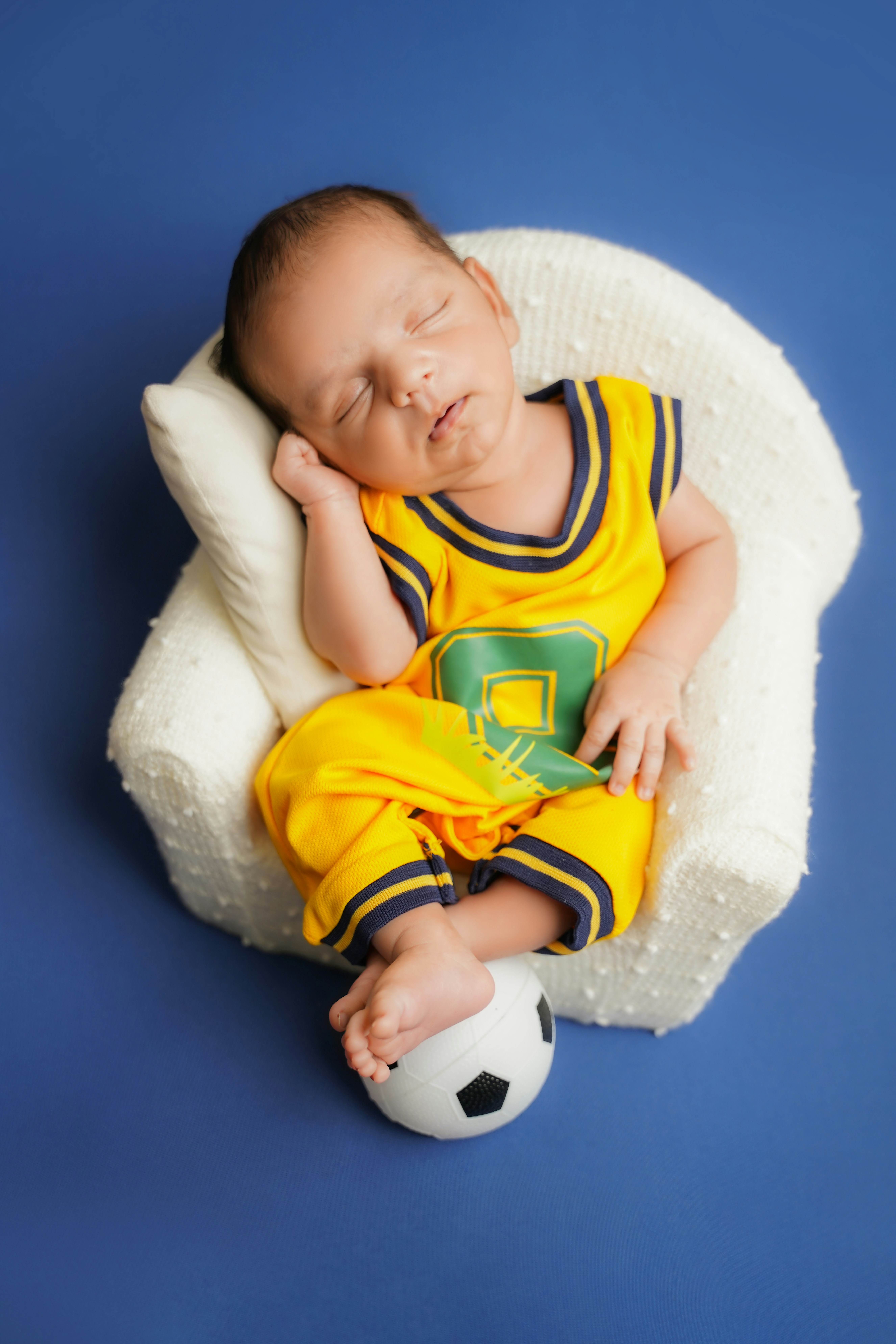 Neon-Jersey Nap: A Sleeping Baby Reposes by a Tiny Soccer Ball