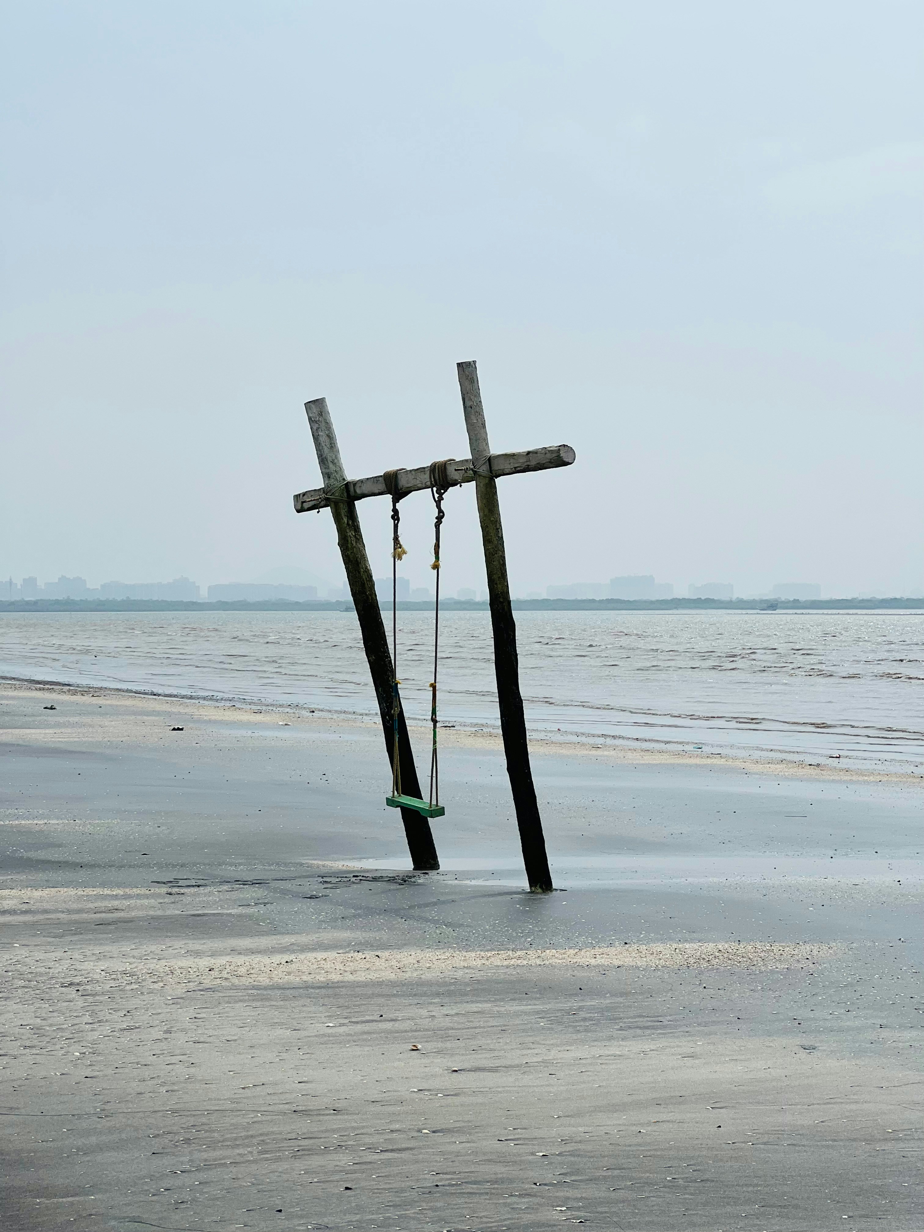 Wooden swing set partially submerged in shallow water.