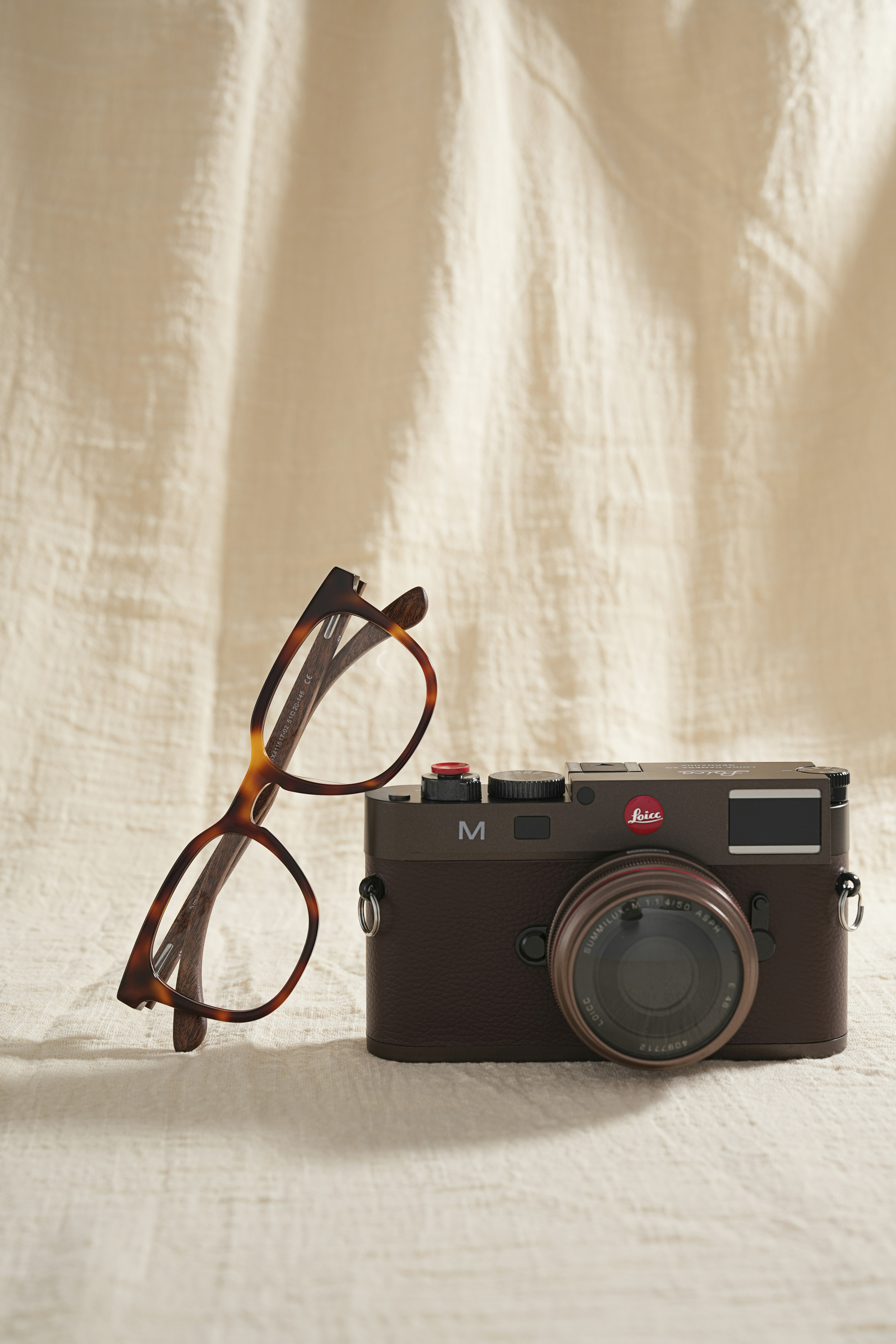 Amber Glasses Rest Against a Vintage Rangefinder on Linen
