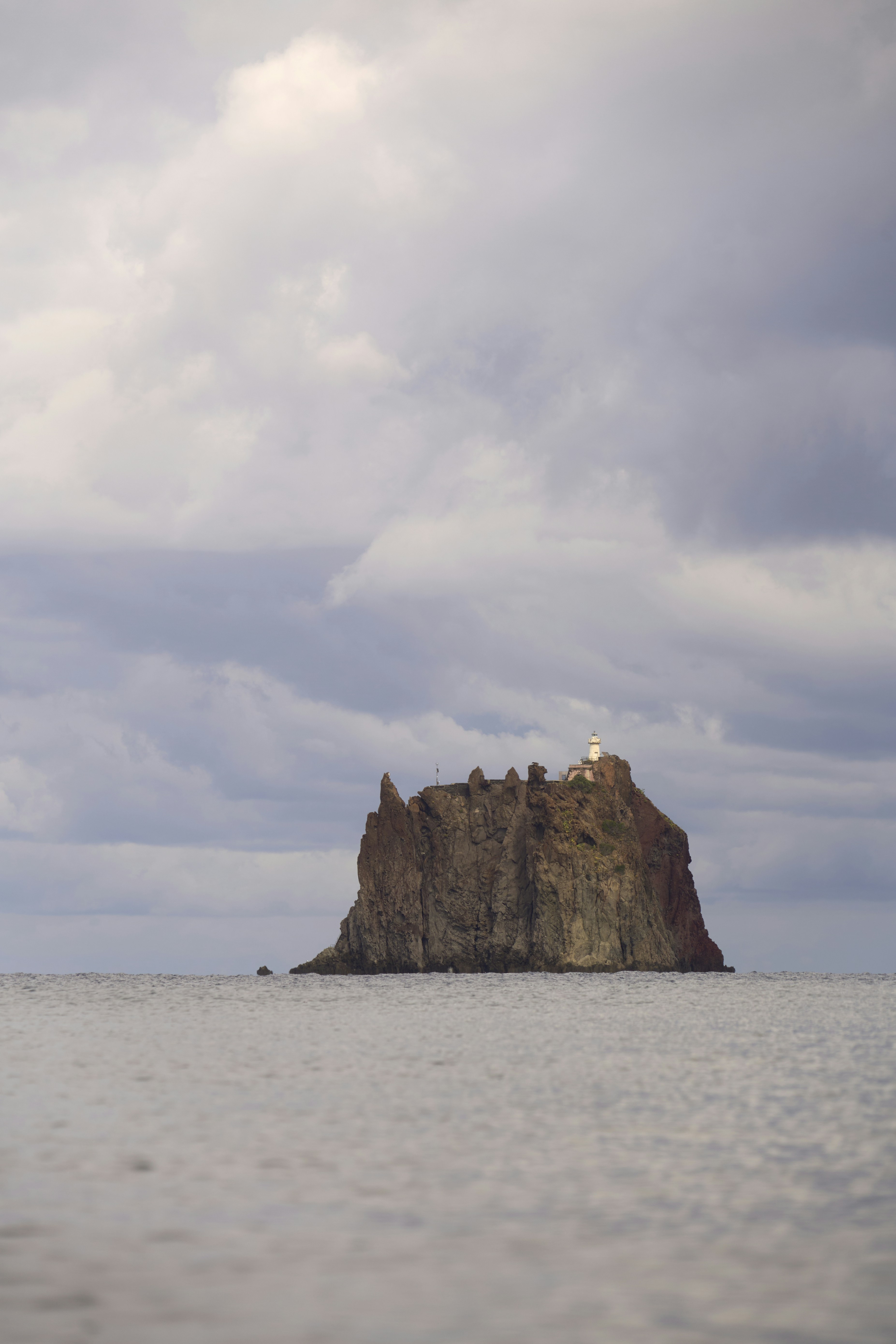 Rocky island with lighthouse in the ocean.