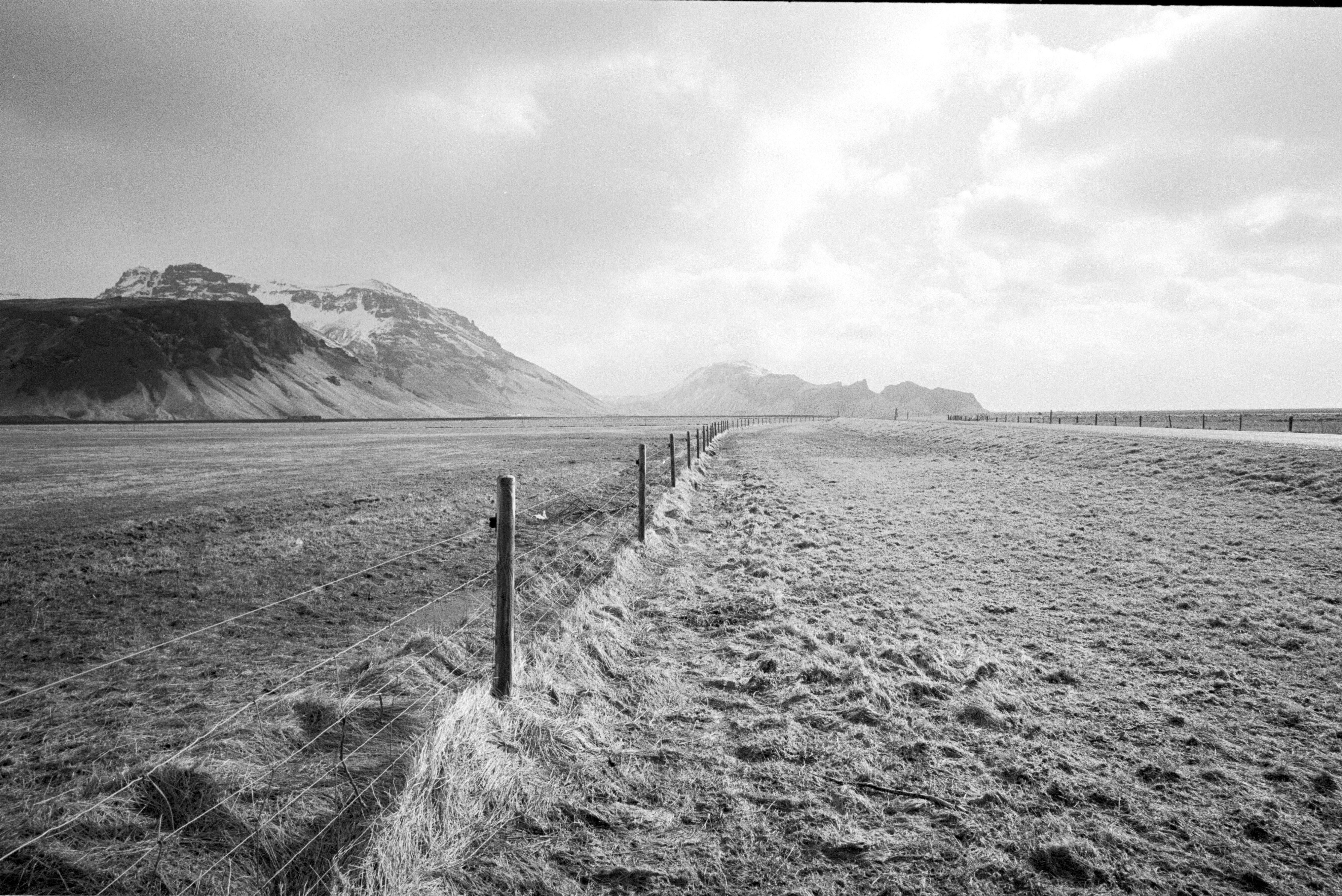 Grassy field with fence and distant mountains