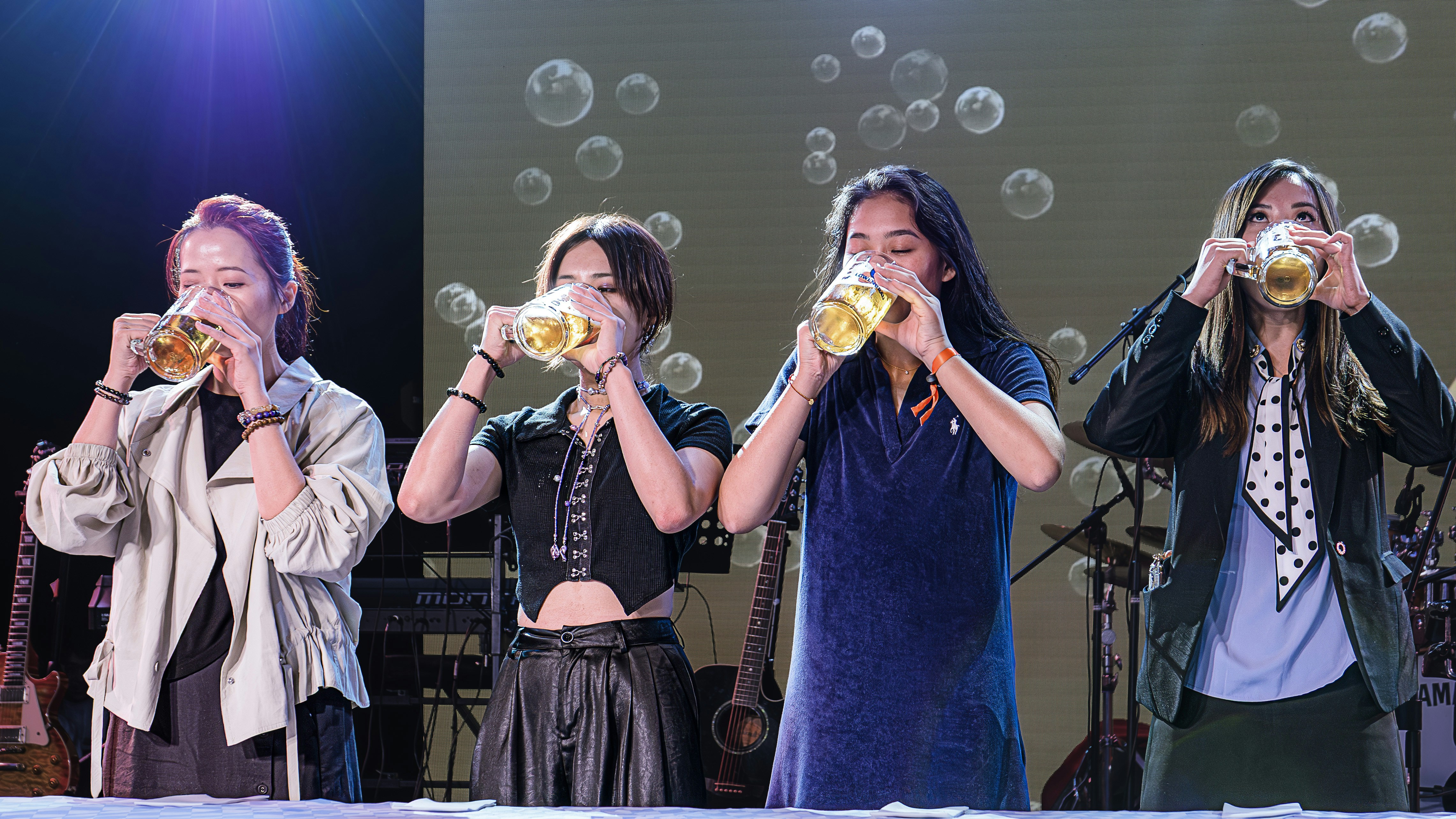 Four women drinking beer from large mugs.