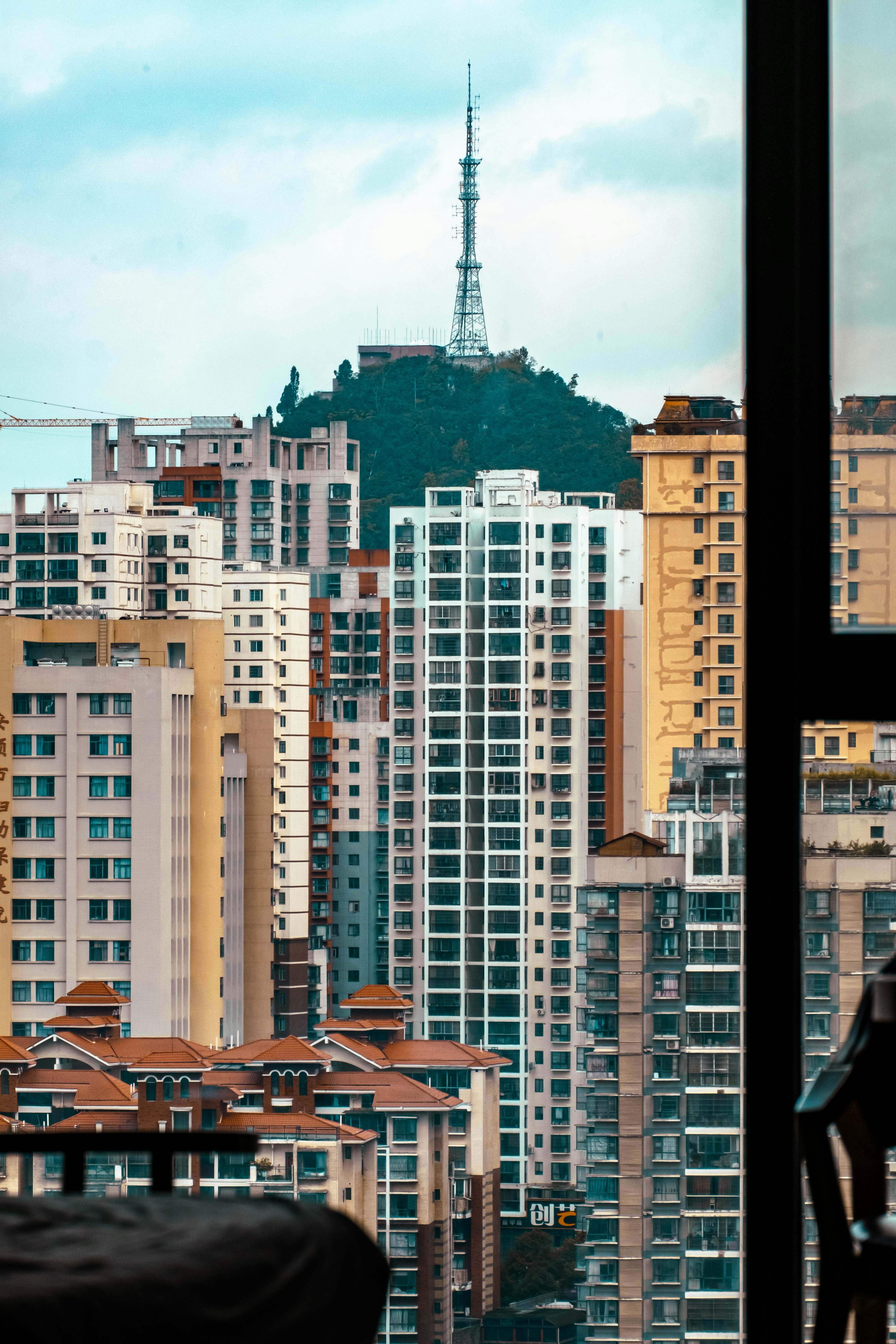 Modern city skyline with a distant tower on hill.