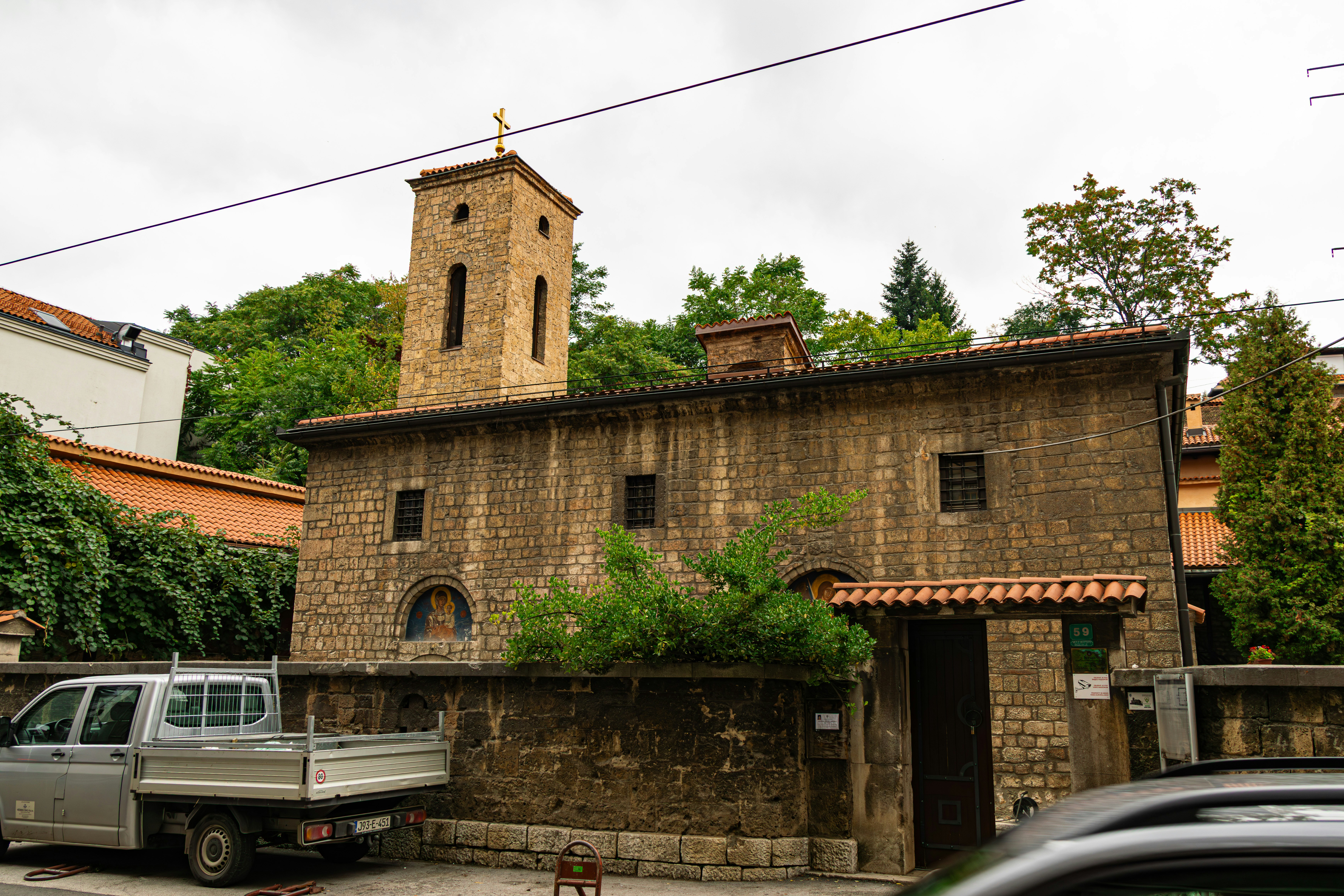 Stone Church on a Quiet Street: Tower, Wall and Greenery Framing a Suburban Moment